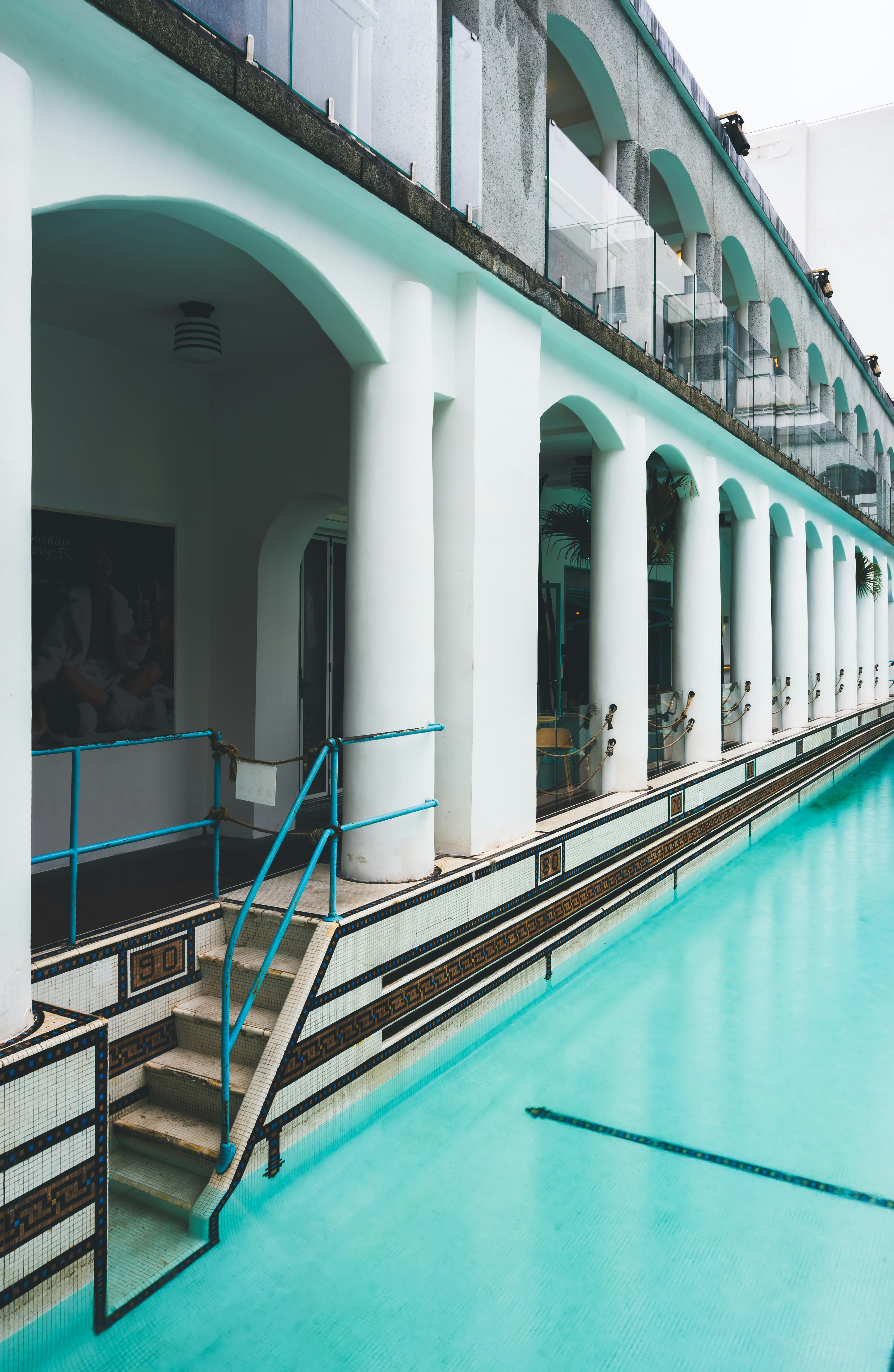 Aquatic Corridor: Archways and Turquoise Reflections along a Poolside Arcade