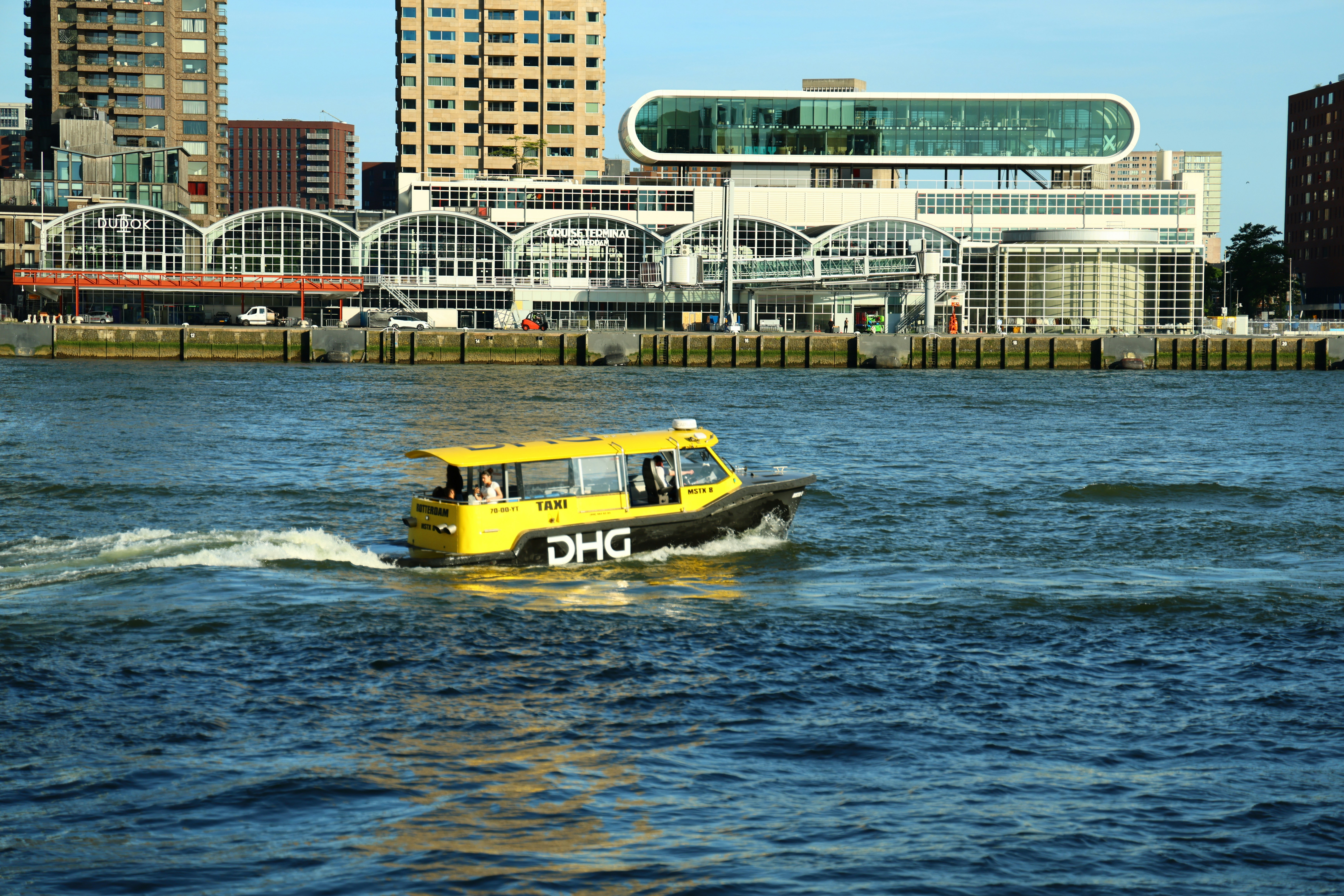 Yellow DHG Shuttle Slices Across the River with an Urban Waterfront Backdrop
