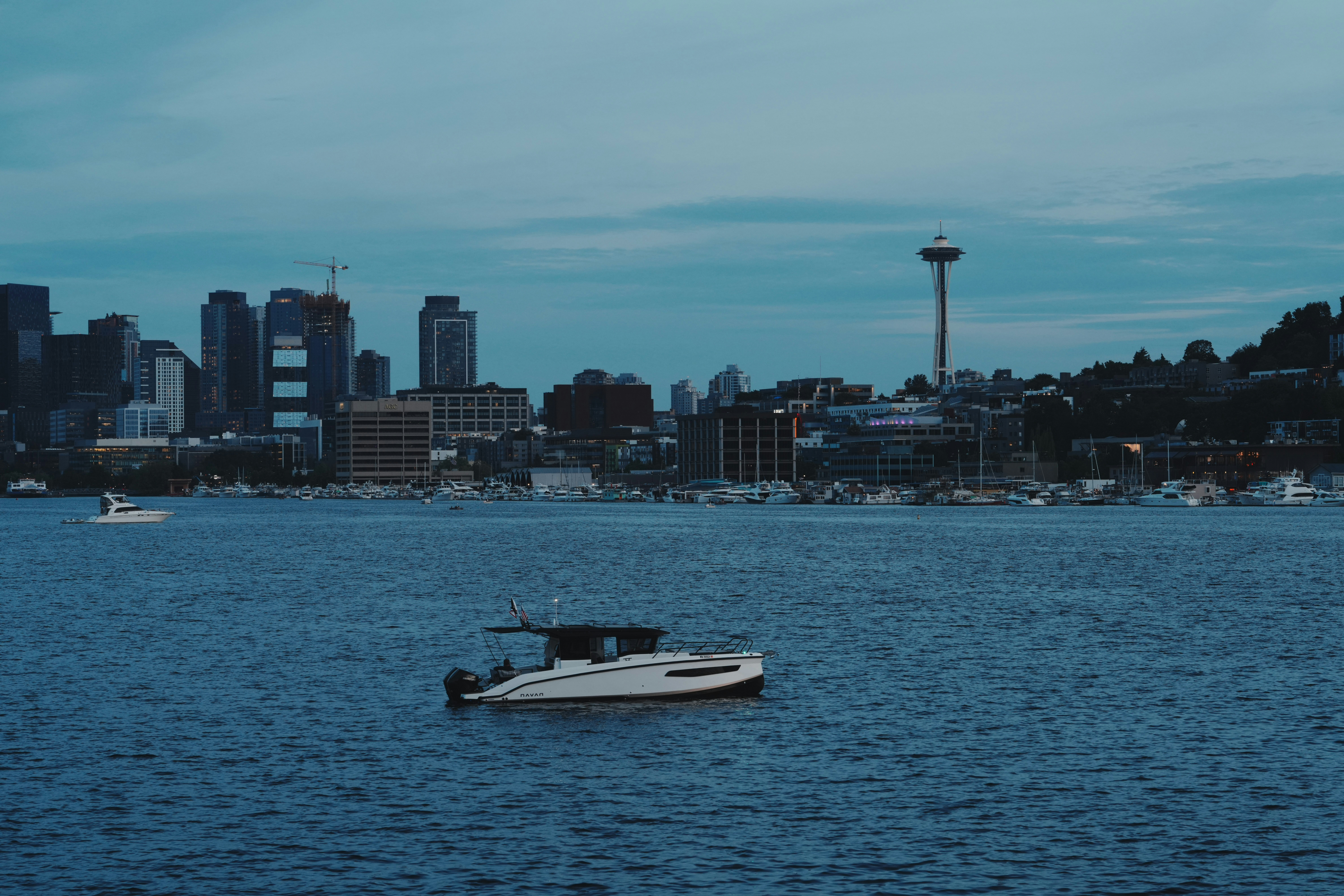 Boat in blue-tinted harbor with skyline silhouette