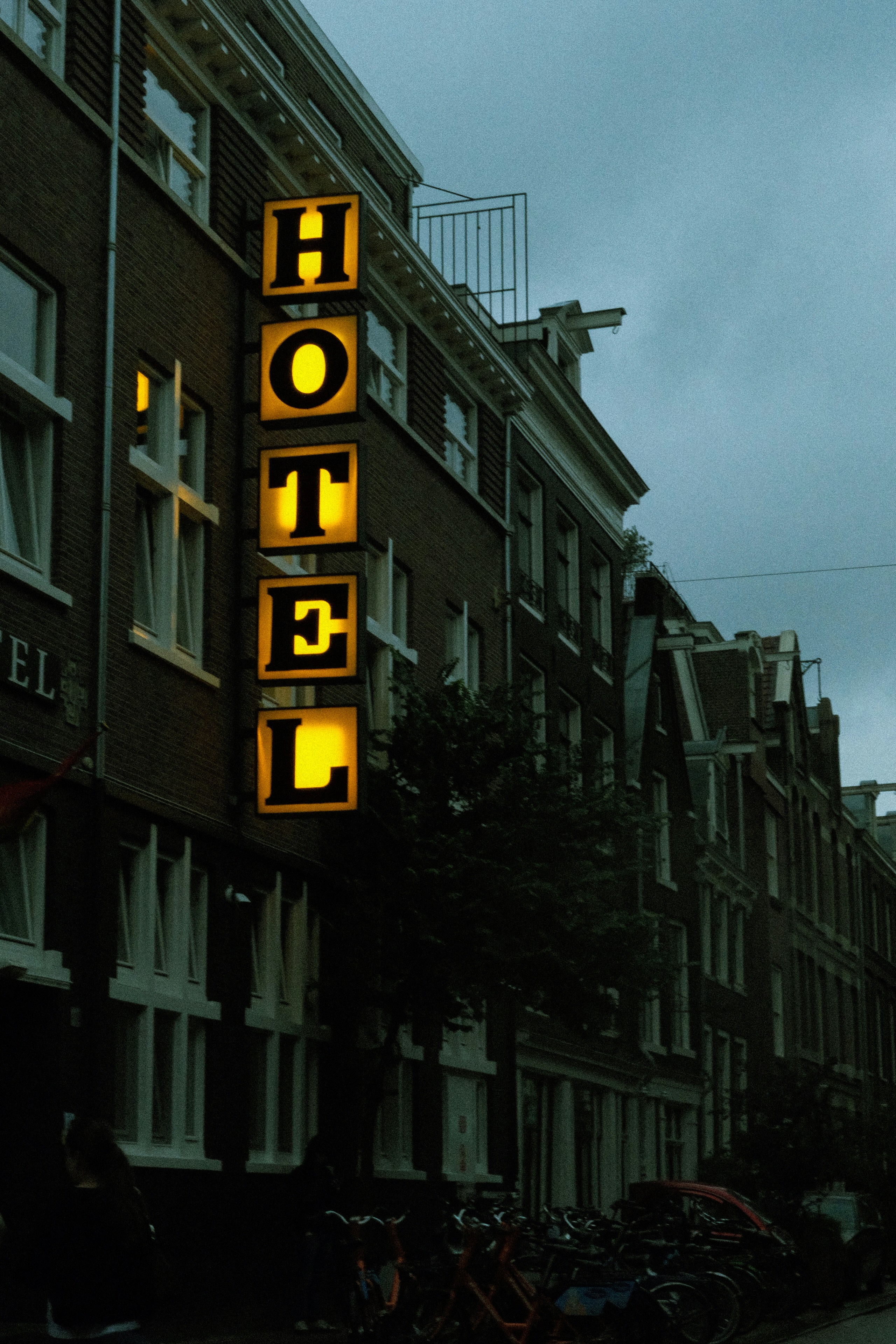 Neon Hotel Sign Cast in Dusk on a European Street
