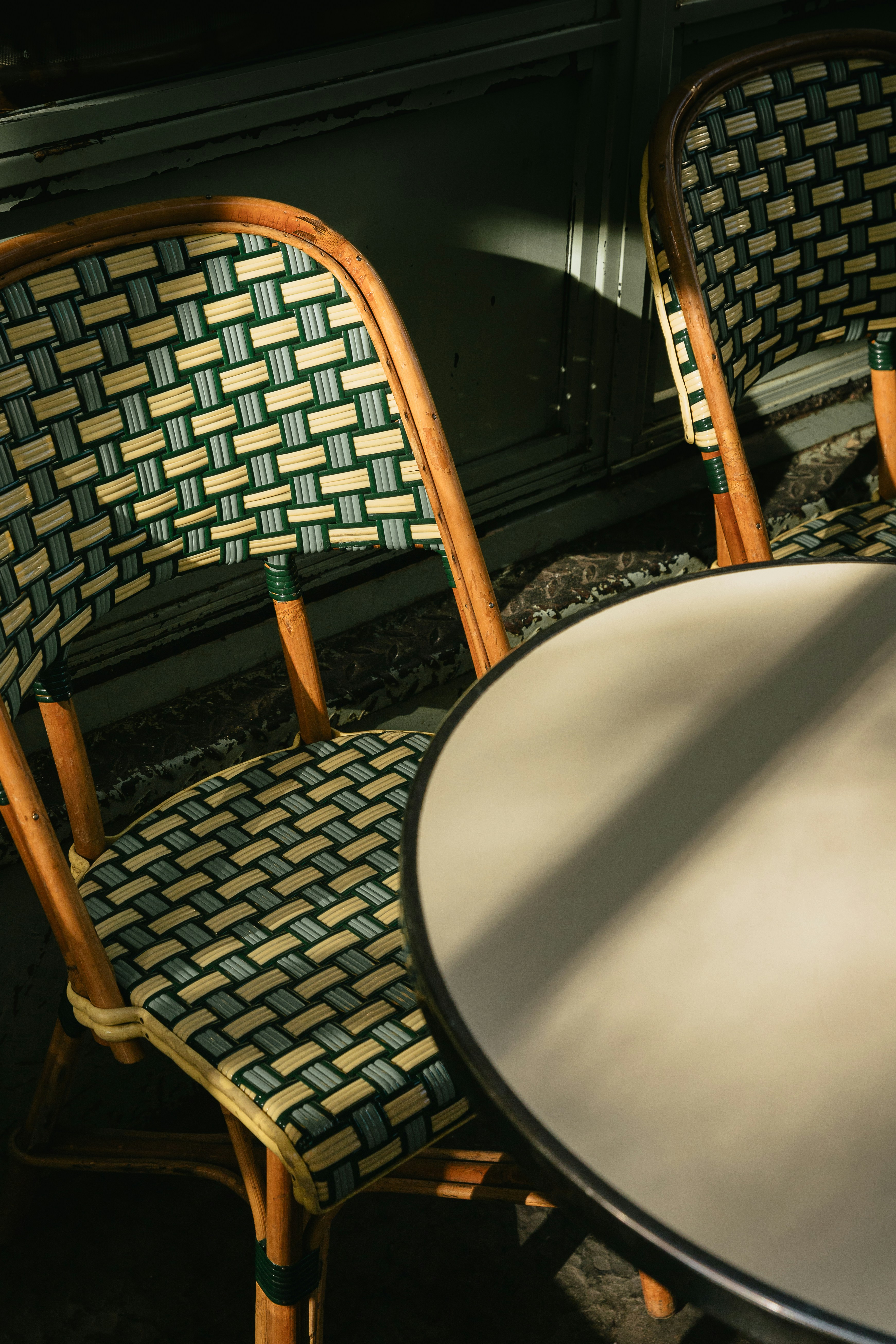 Sunlit Bistro: Woven Chairs Bathed in Shadow on a Quiet Terrace