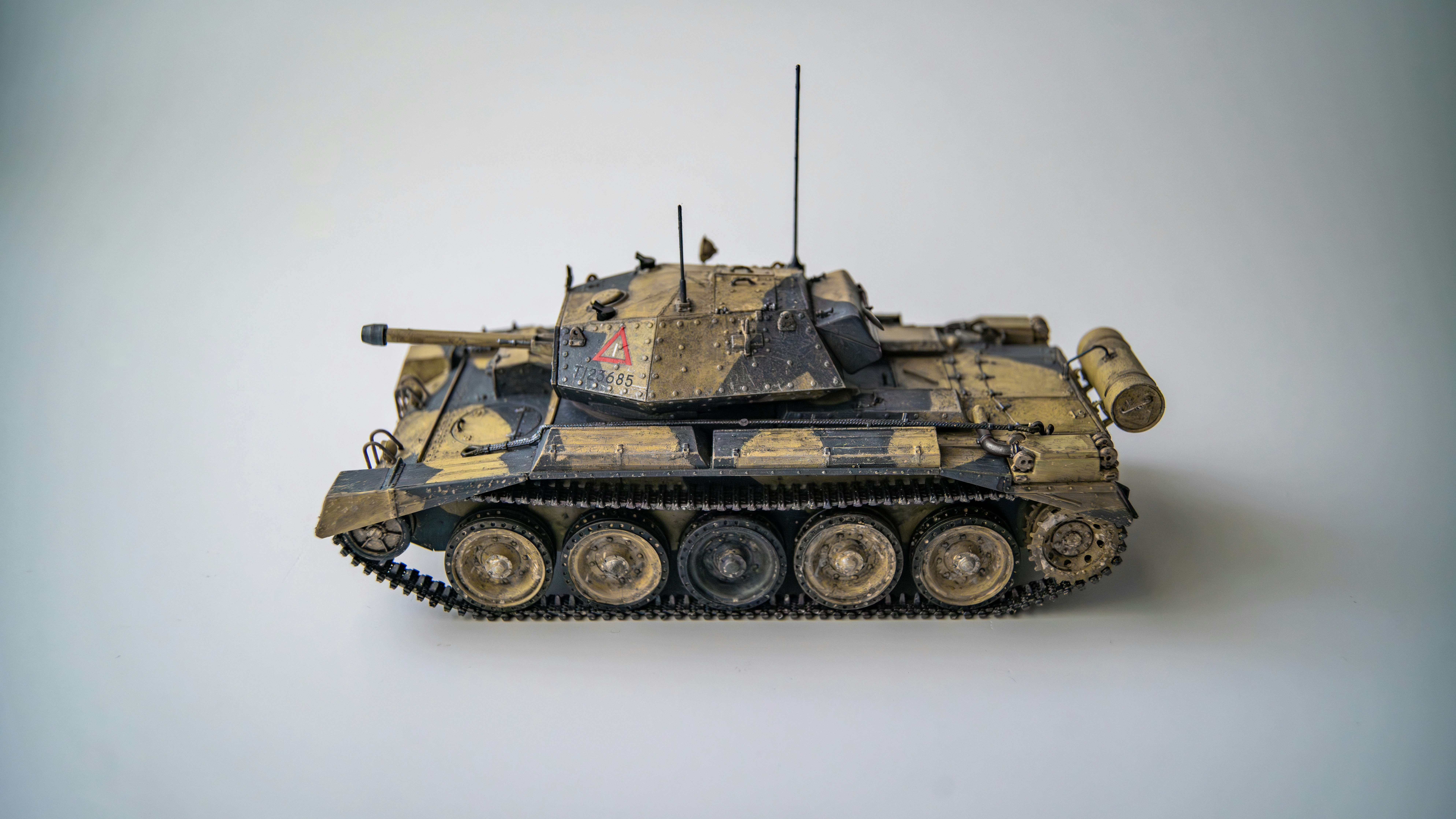 Small-scale armored tank model posed on a neutral backdrop, showing weathered camouflage and detailed tracks for display photography.