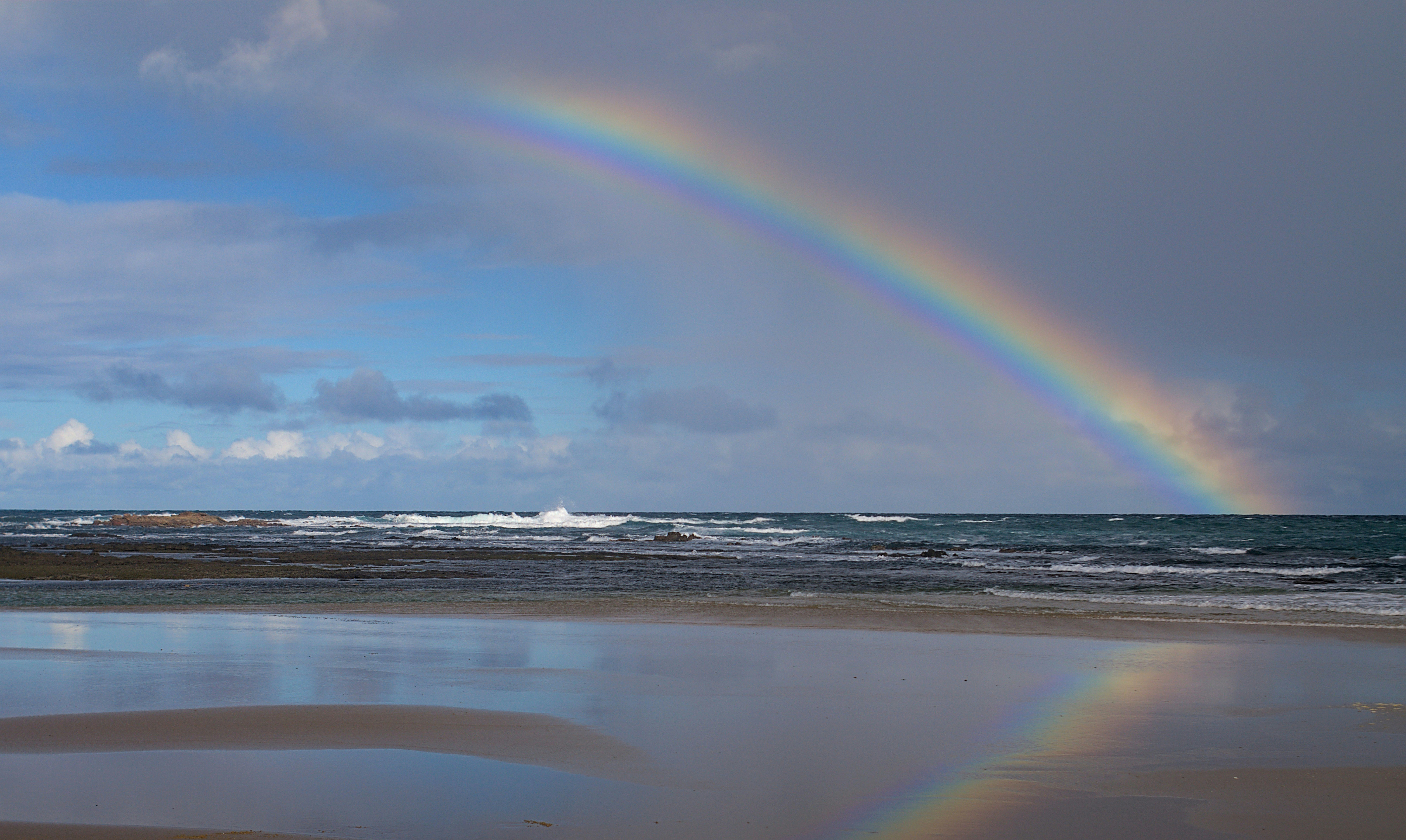Stellar Arc: A Wide Rainbow Over Quiet Shoreline