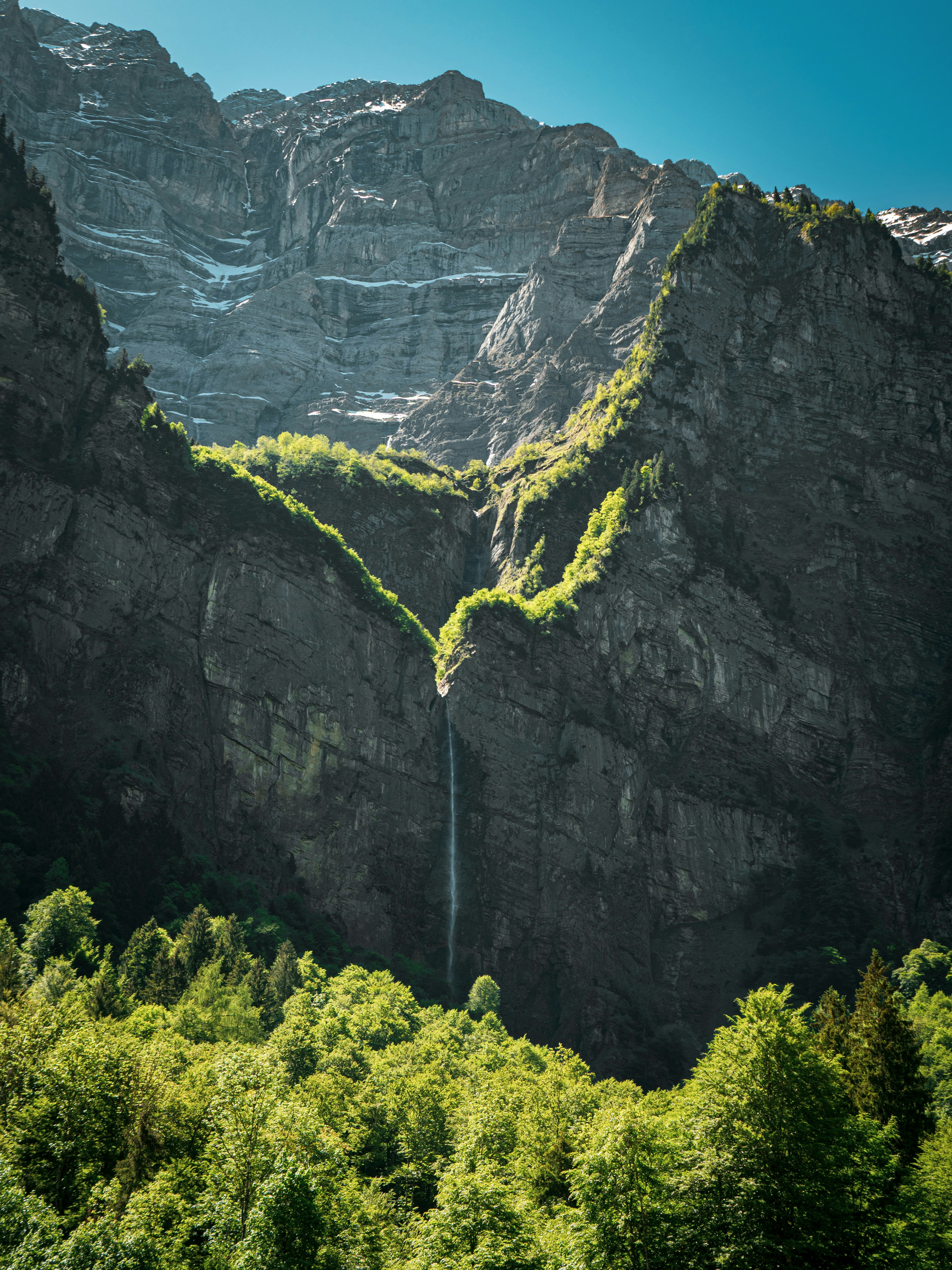 Cascade Amid Granite: A Narrow Vein of Green Between Towers