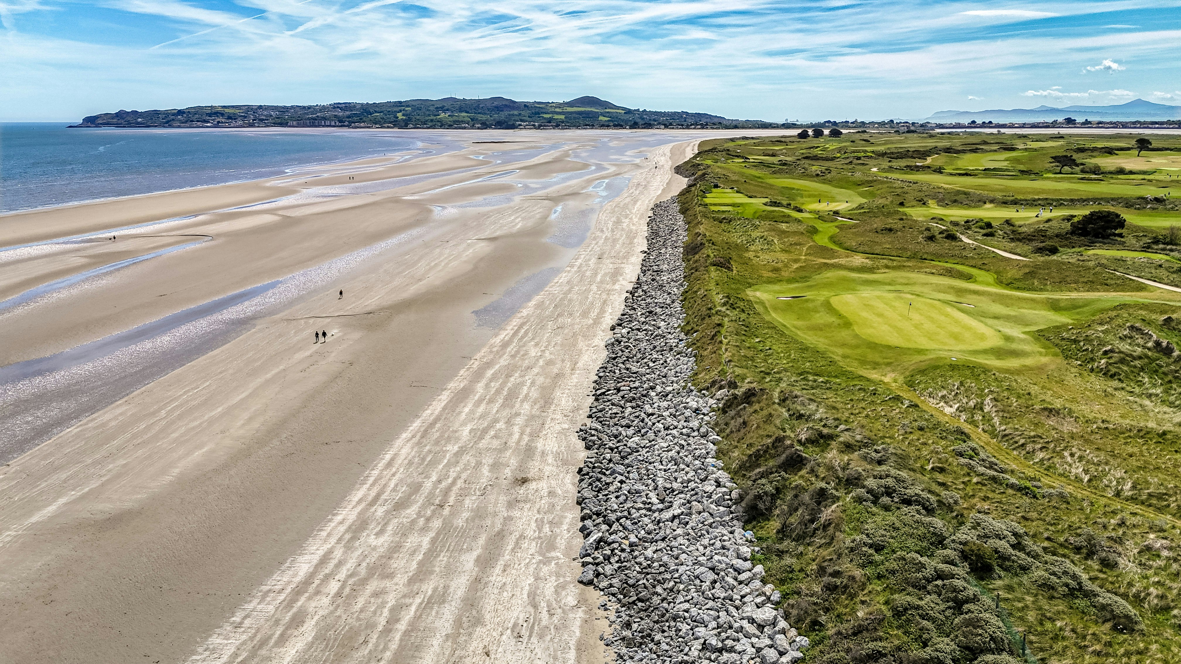 Coastal Divide: Beach Meets Green Fairway Under Wide Sky