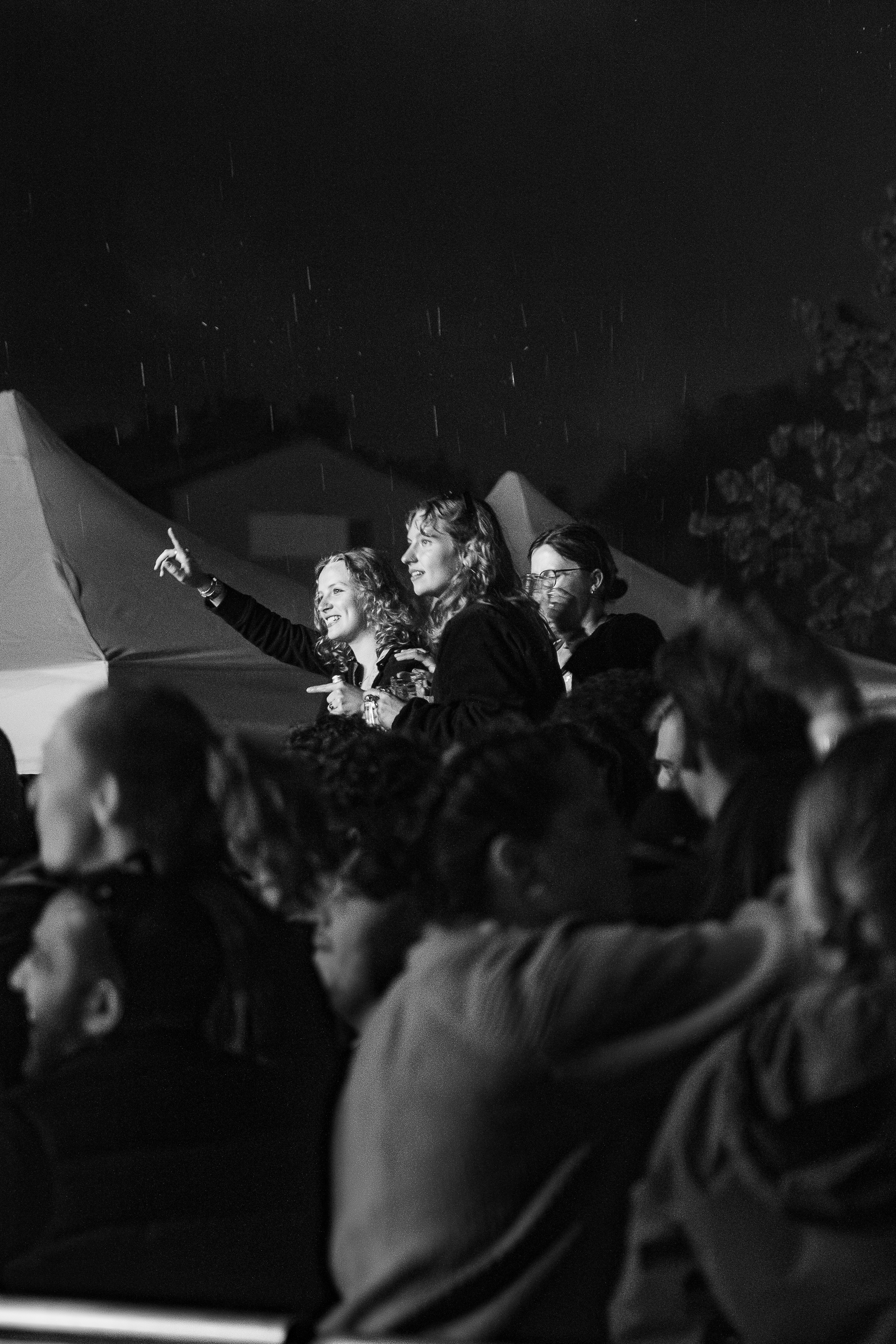 Night Crowd Gaze: A Close-Up of Enthralled Faces Under Rain and Tents