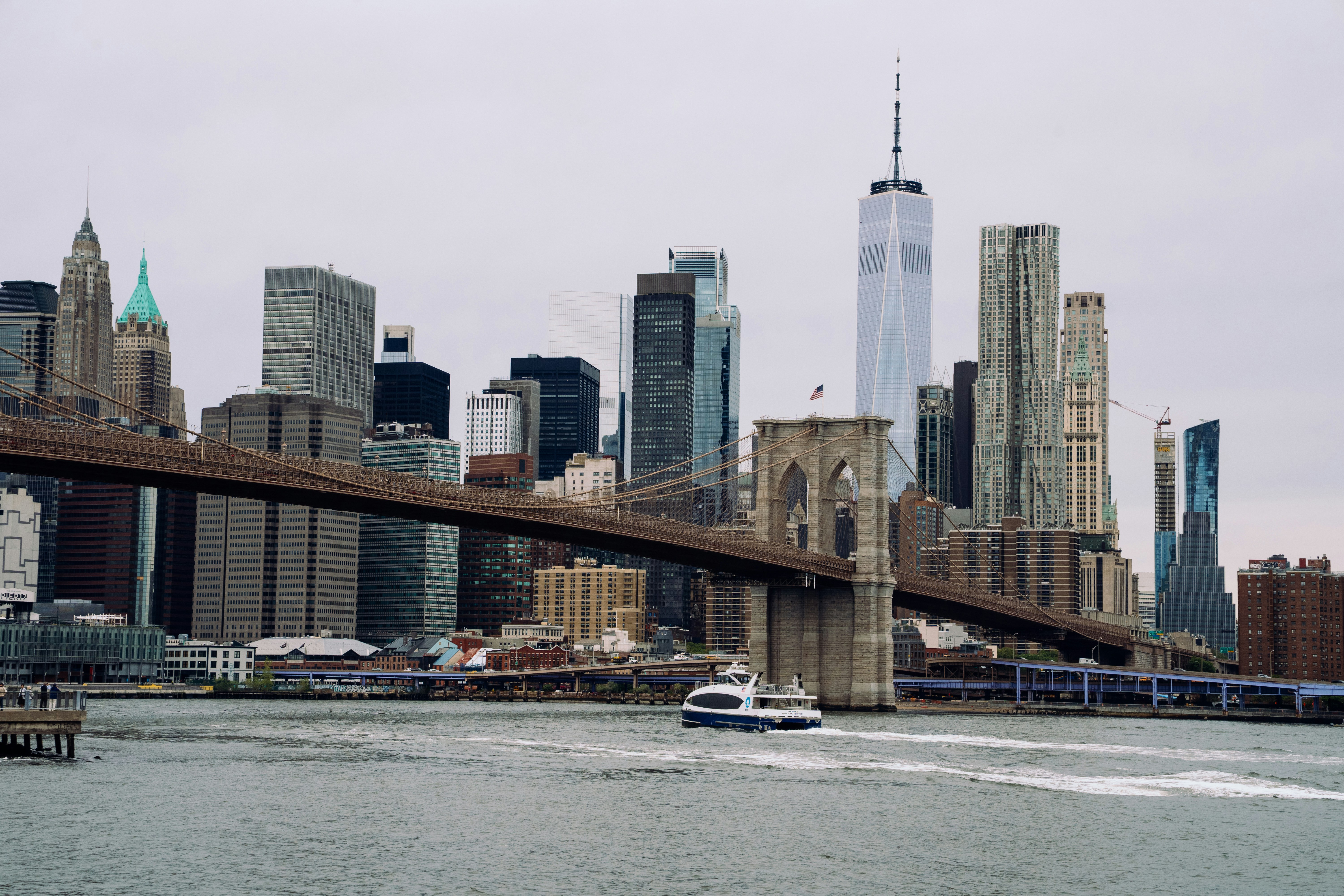 Bridge and skyline through the East River: a ferry glides beneath towering towers