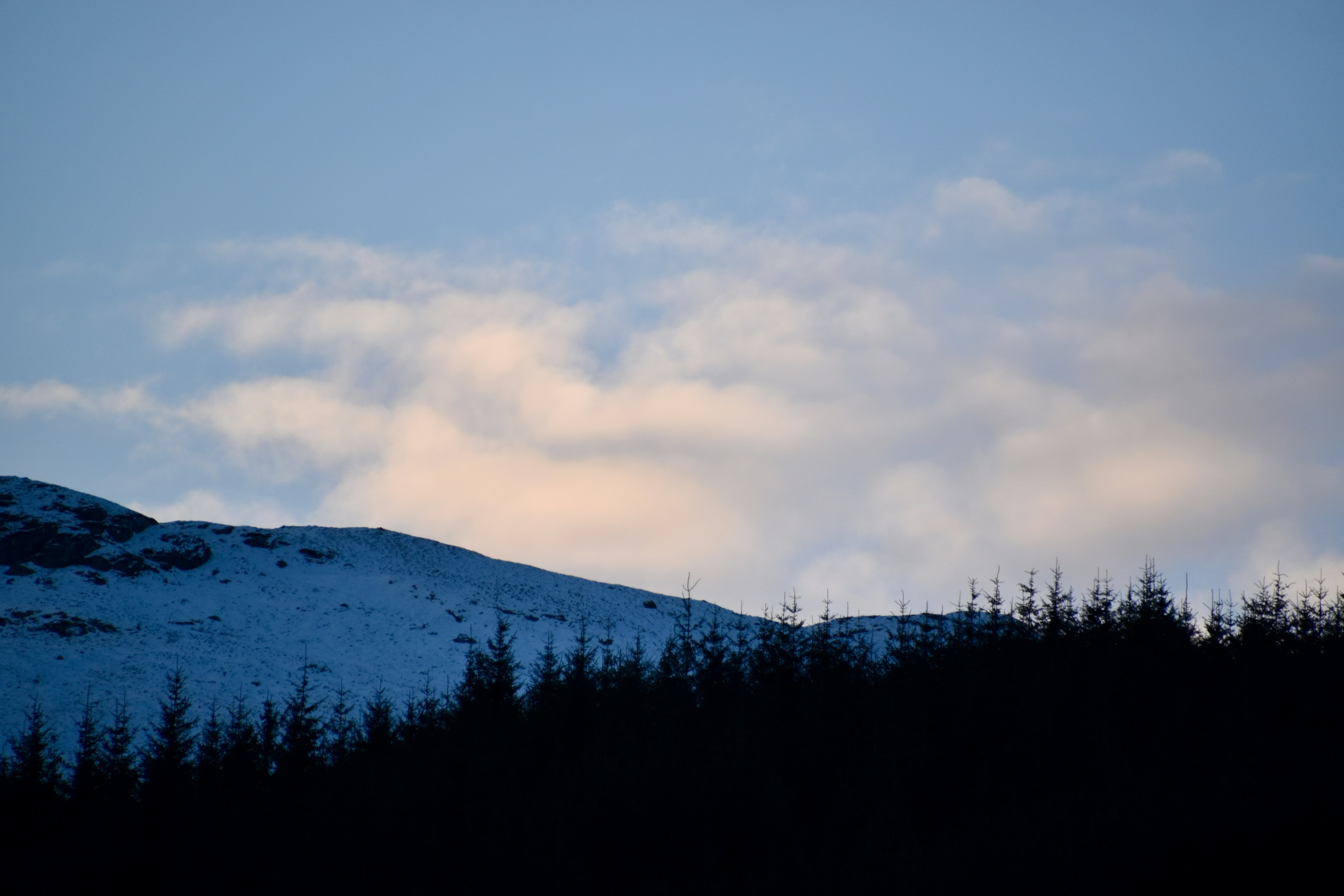 Blue Hour Silhouette: Snow-Capped Ridge Beneath Soft Clouds