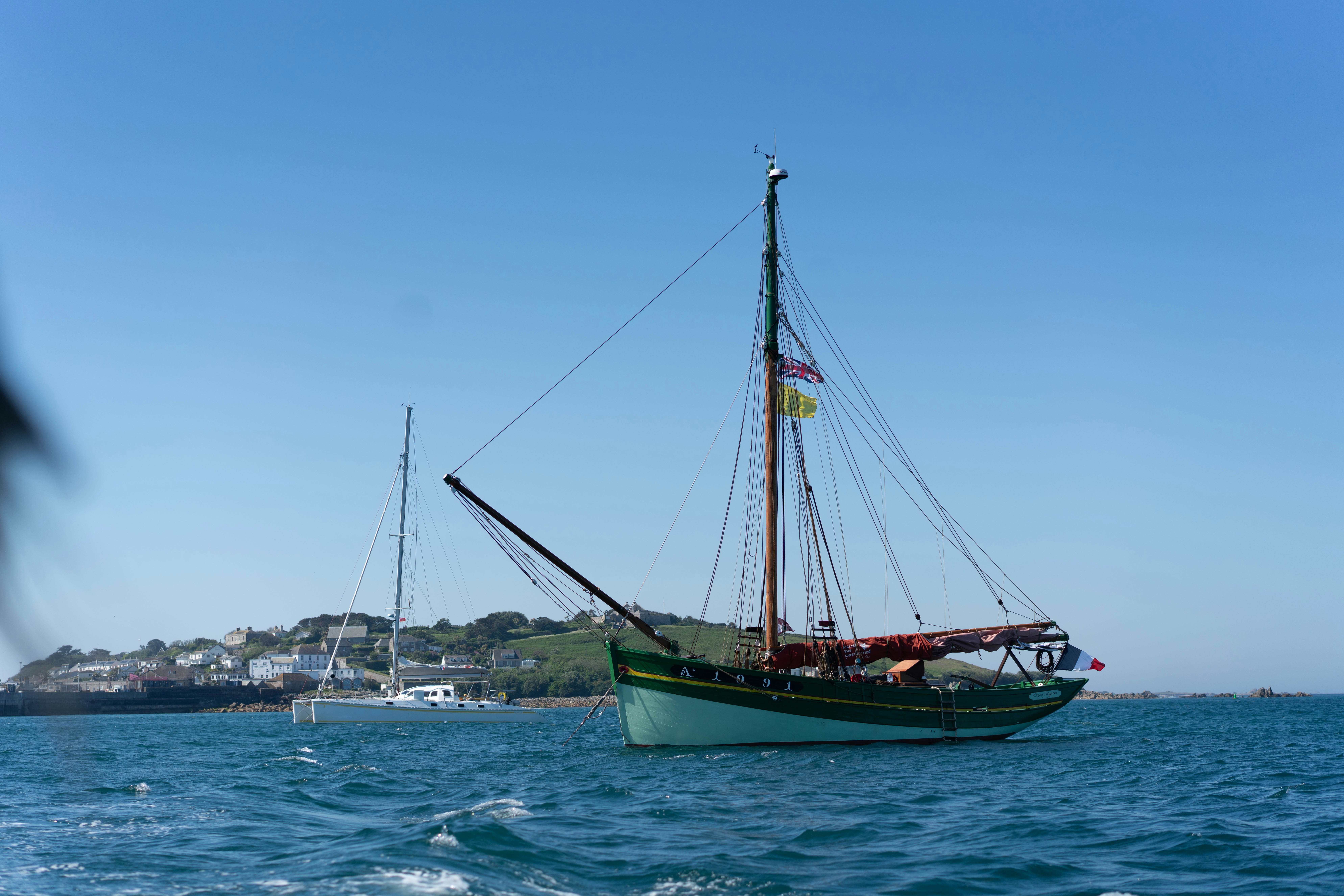 Green-hulled schooner rests on a calm blue sea under a clear sky
