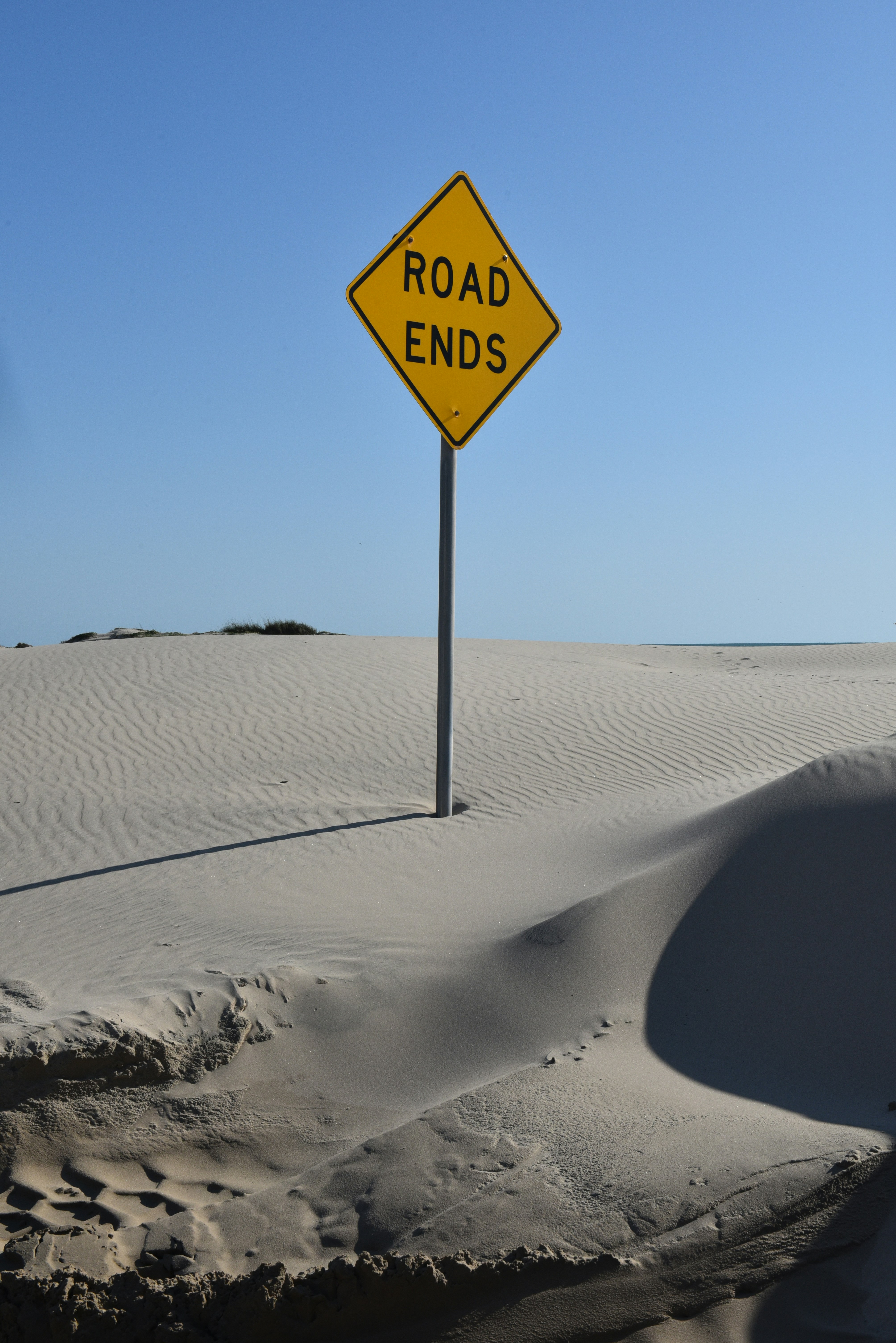 Deserted Highway of Sand: A Lone Road End Sign Among Dunes