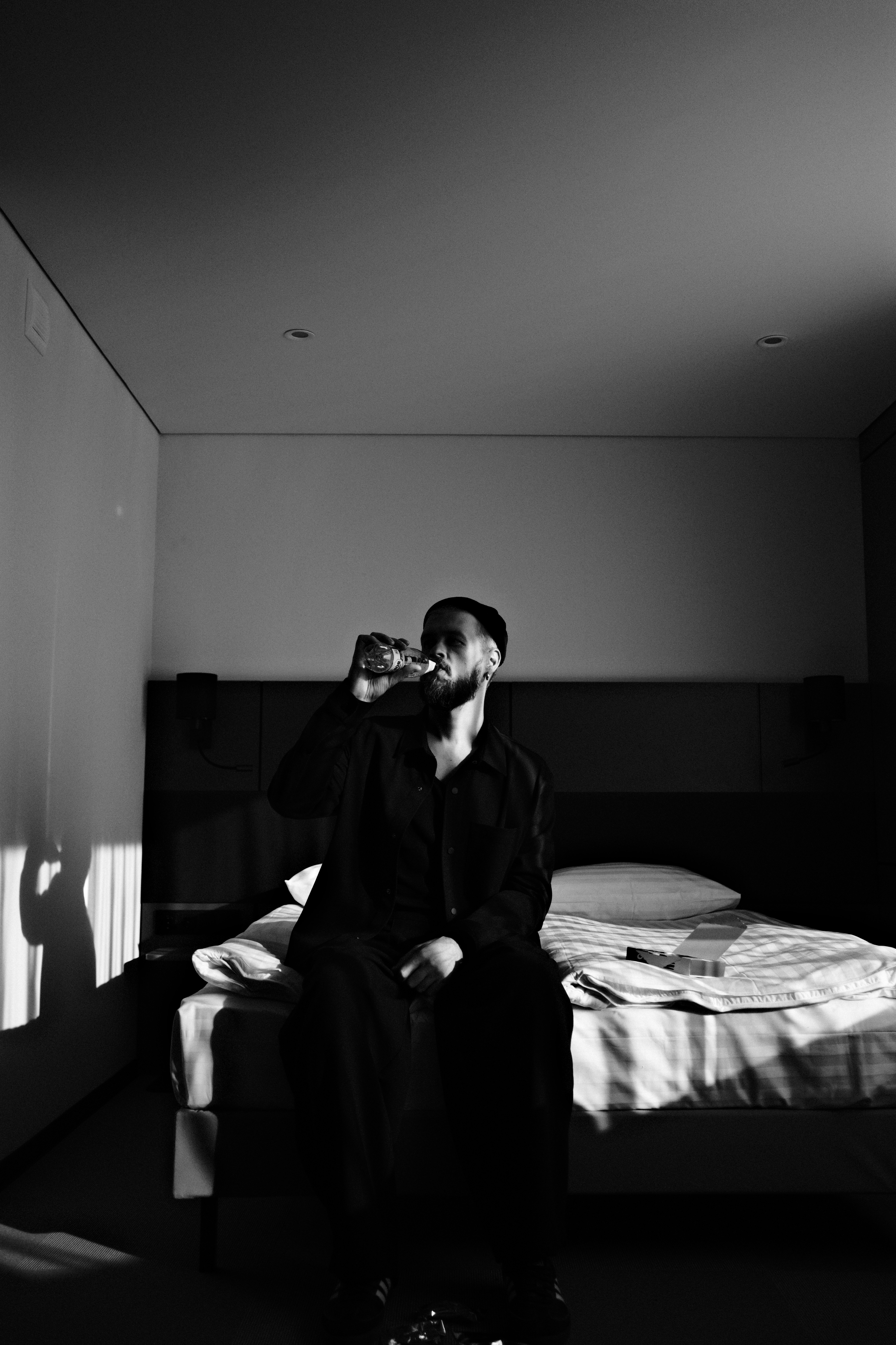 Midnight Quiet: A Man in Shadowed Hotel Room Sips a Moment