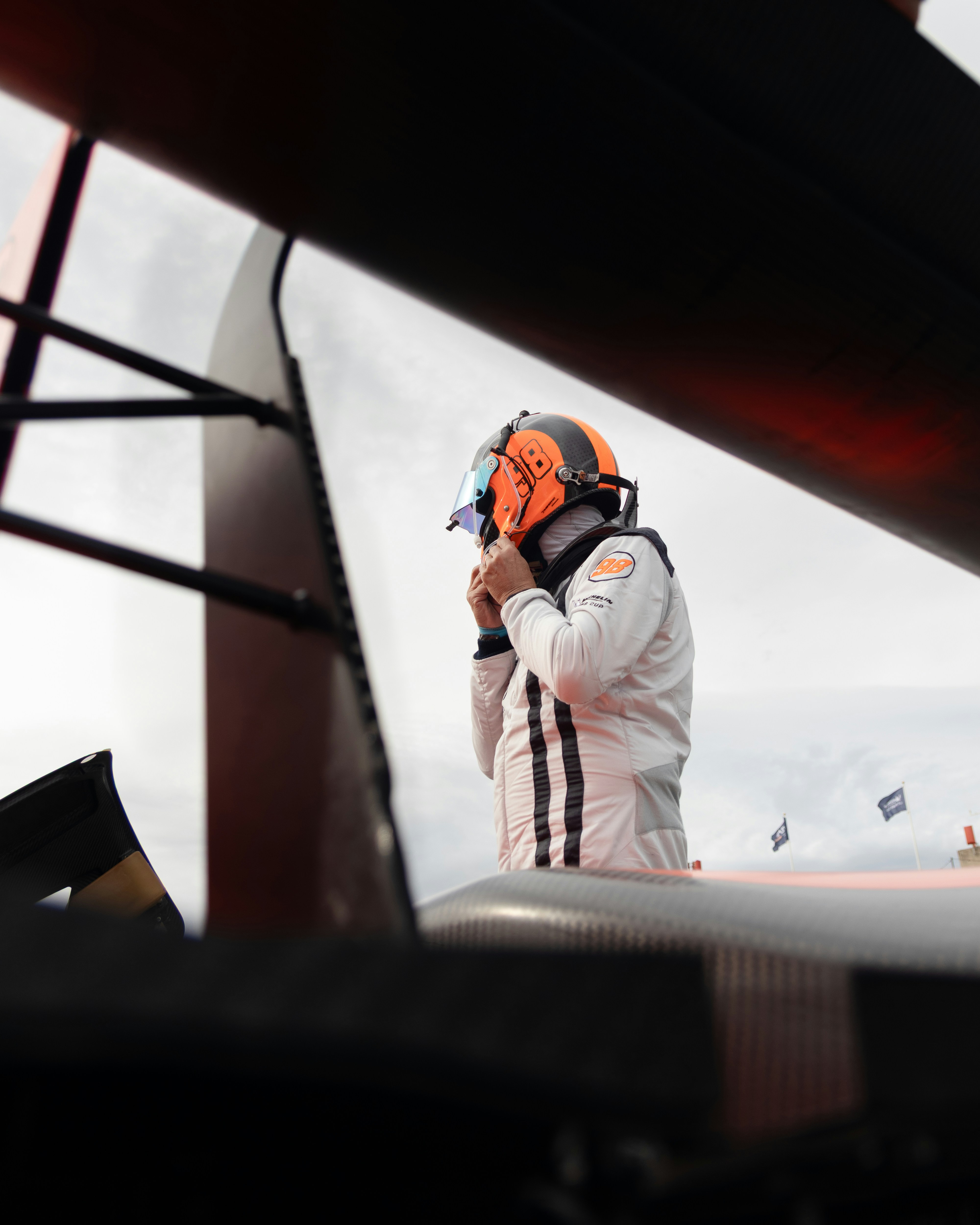 Pilgrim of the Cockpit: A Pilot in White Holds the Helmet Amidst Structural Shadows