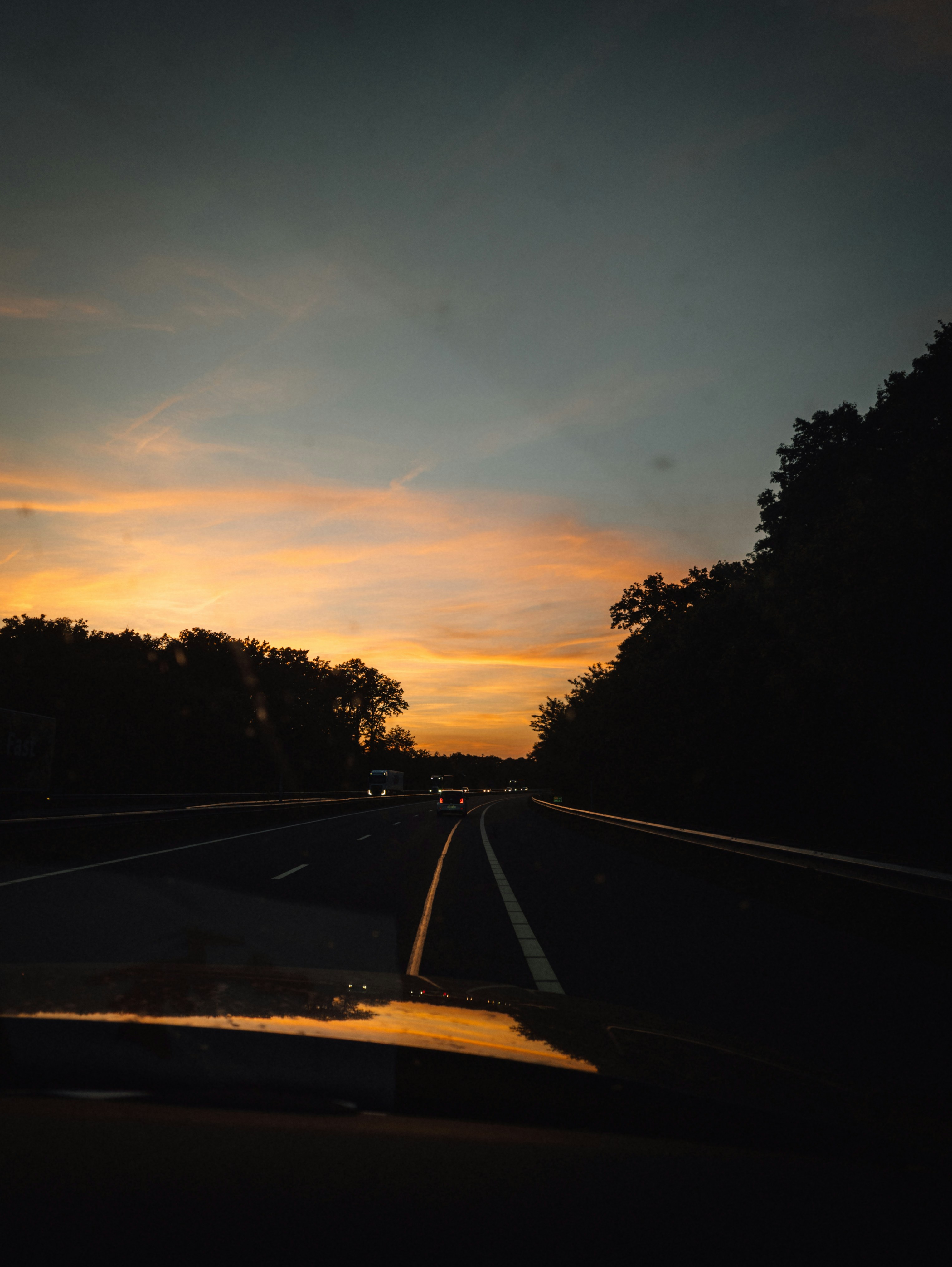 Twilight Toll: Highway Silhouettes Beneath a Candlelit Sky