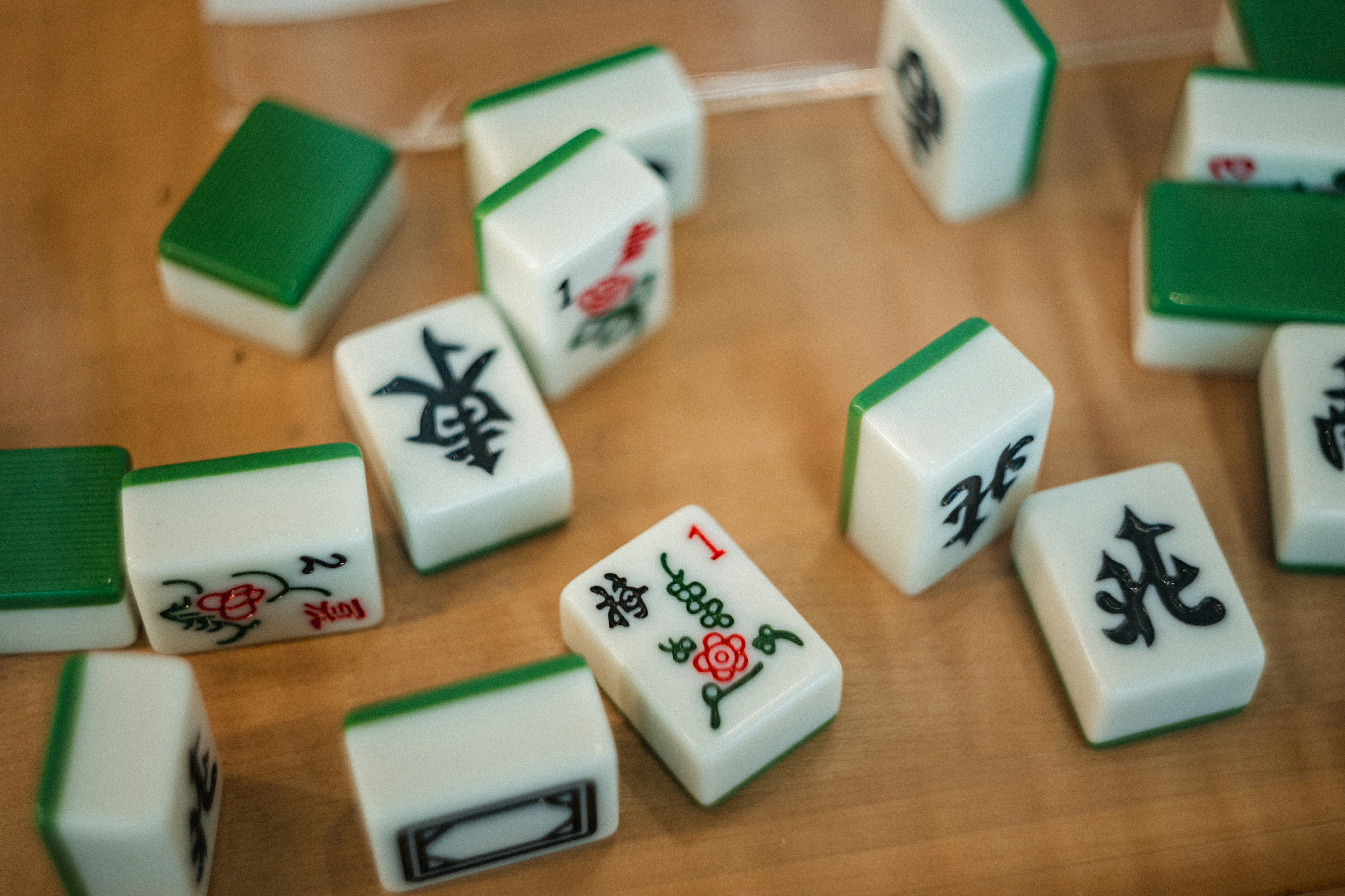 Tiles in Motion: A Throw of Mahjong Pieces Across a Wooden Table