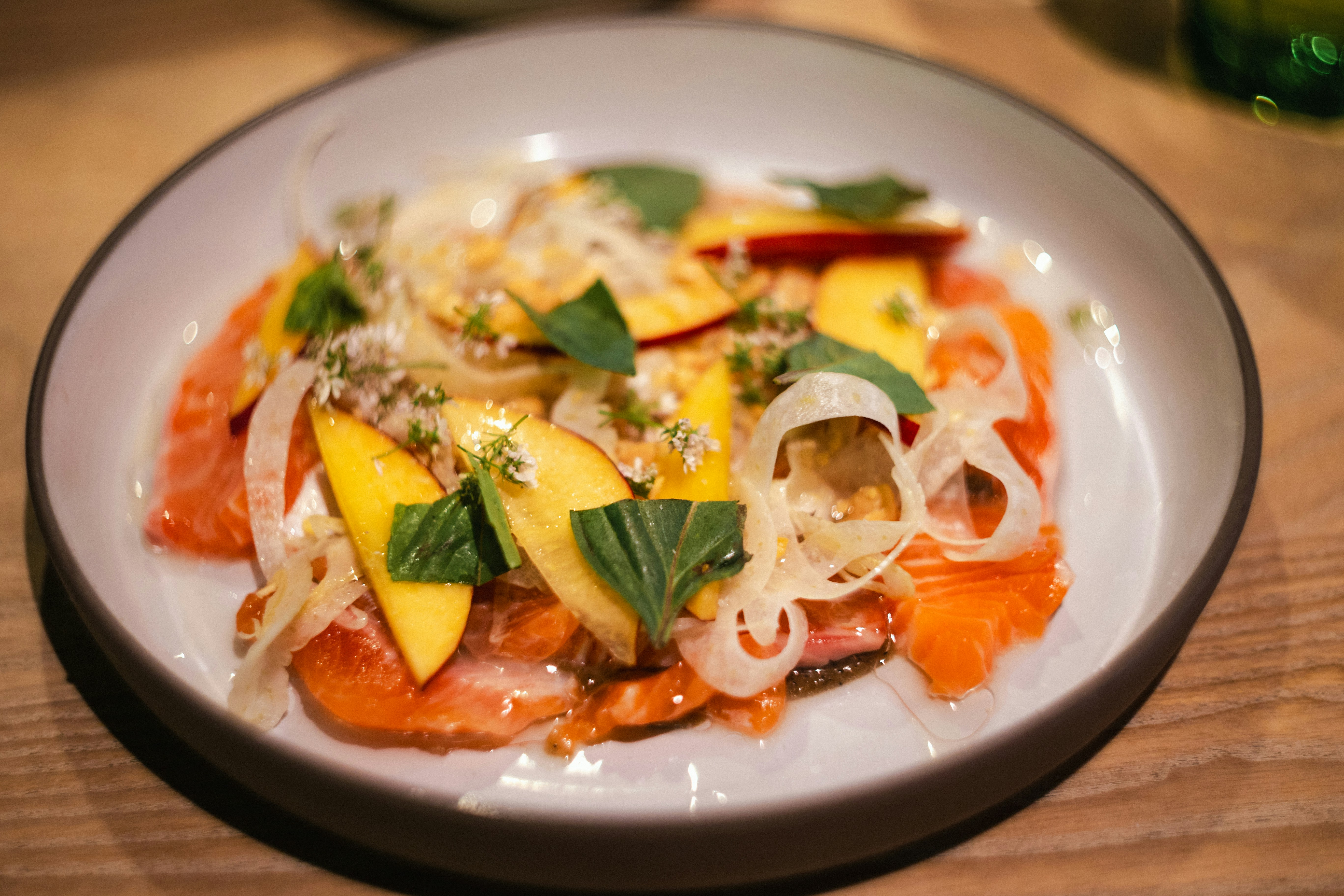 Seasonal Salmon Puroise: Mango, Onion and Herb Garnish in a Shallow Bowl