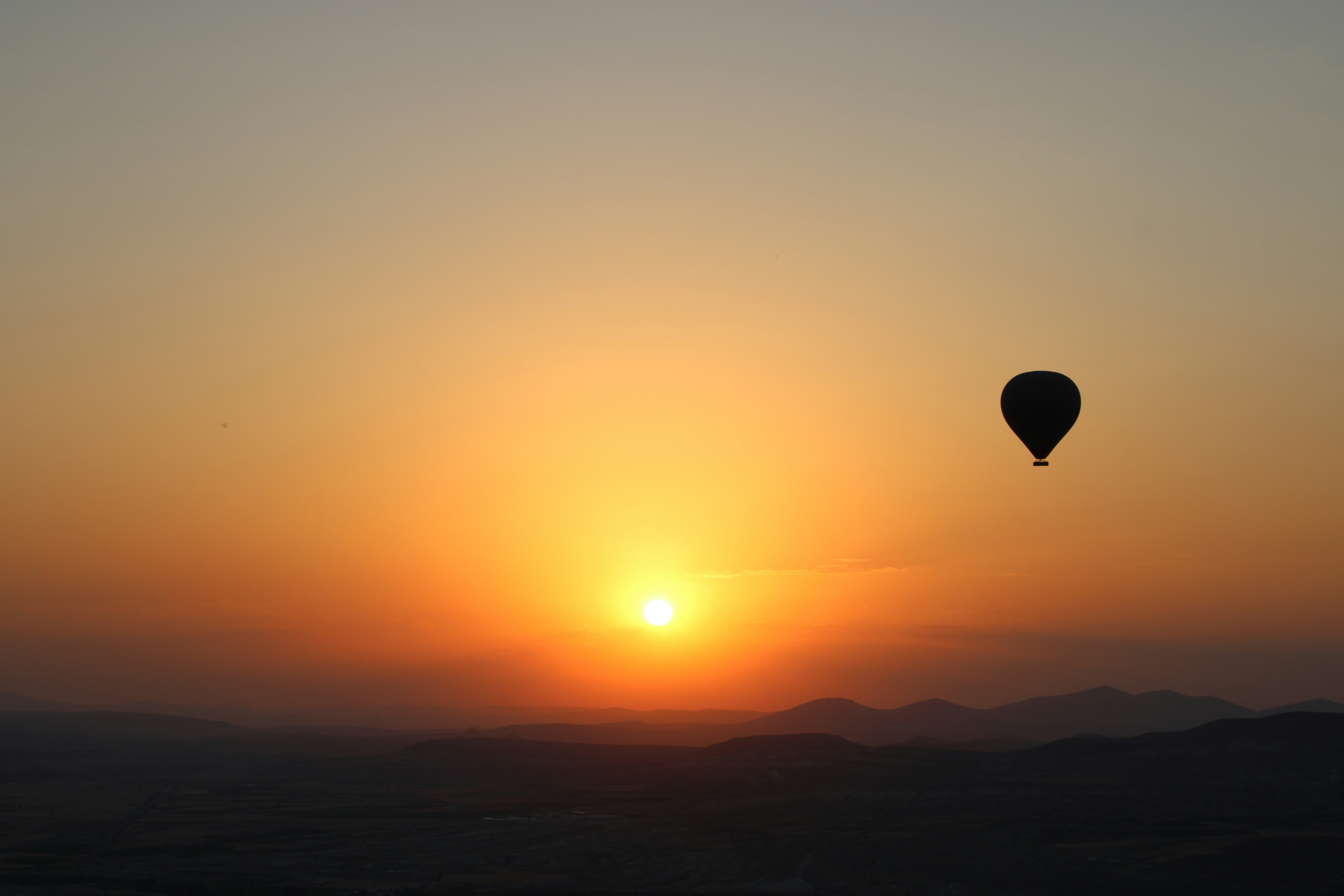 Sunset Atlas: A lone balloon drifts above shadowed horizons