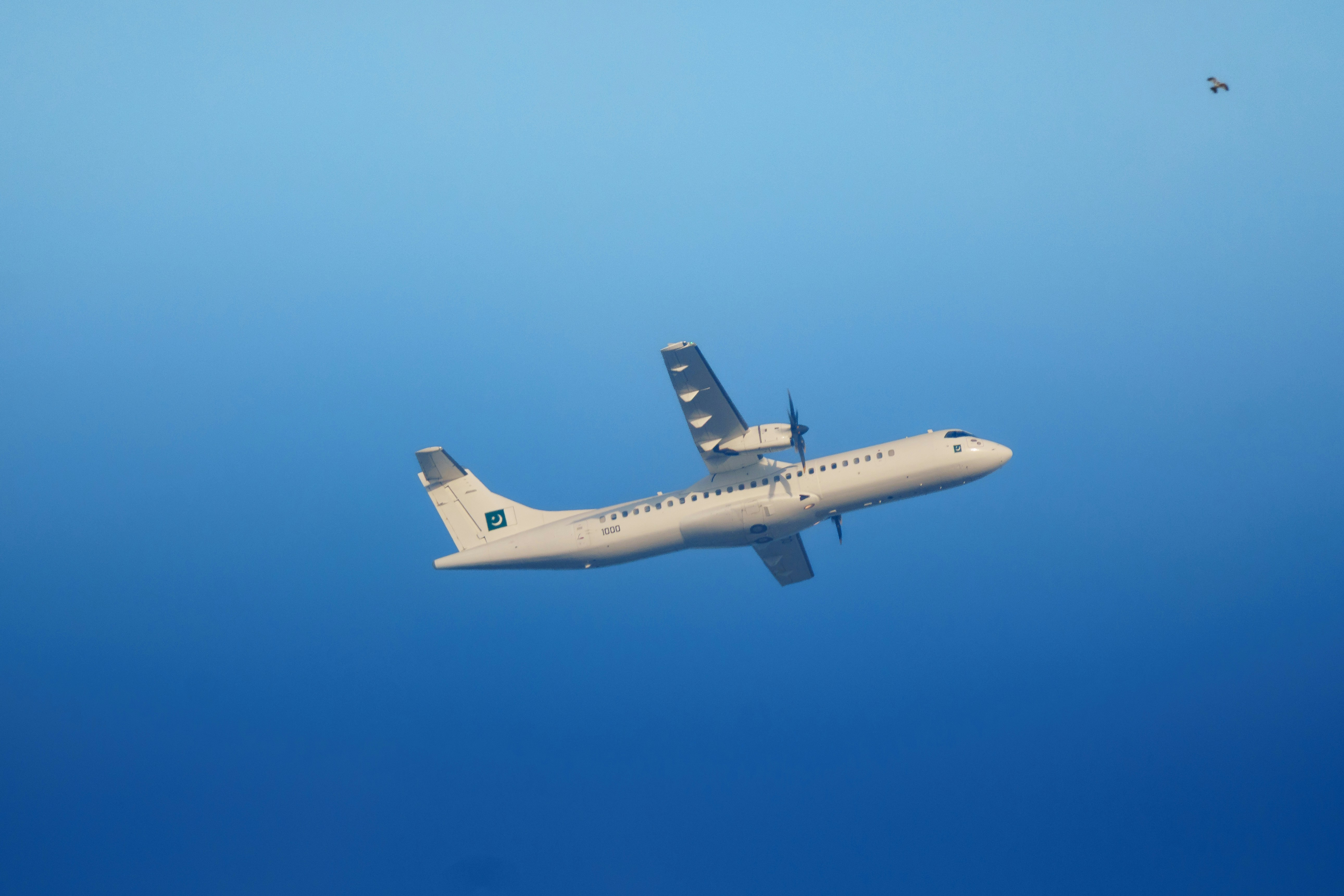 White twin-turboprop aircraft slicing through a cobalt sky