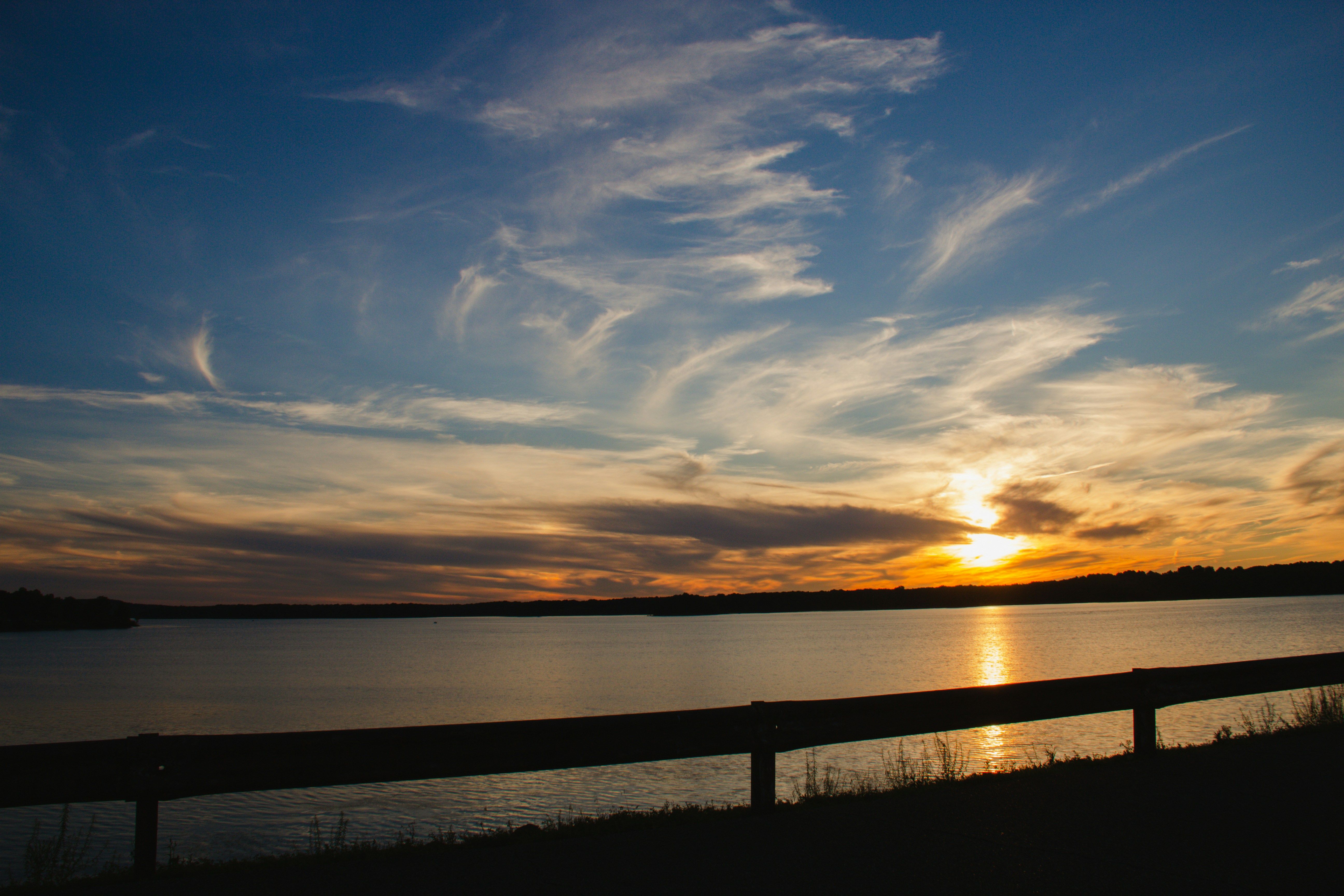 Sunlit Horizon Over Quiet Water with Silhouette Rail