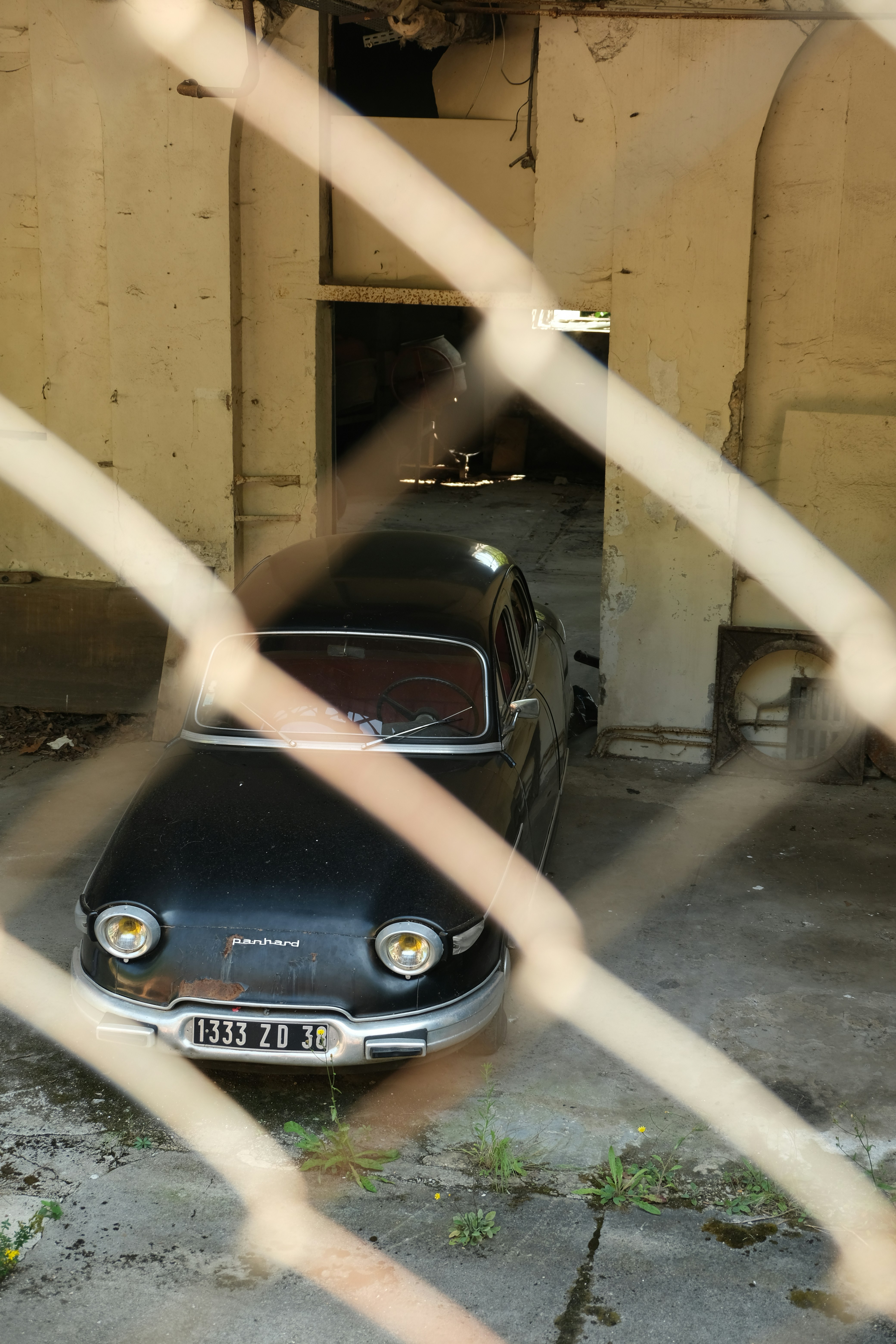 Vintage Sedan in a Dim Garage Framed by Chain-Link Diagonals