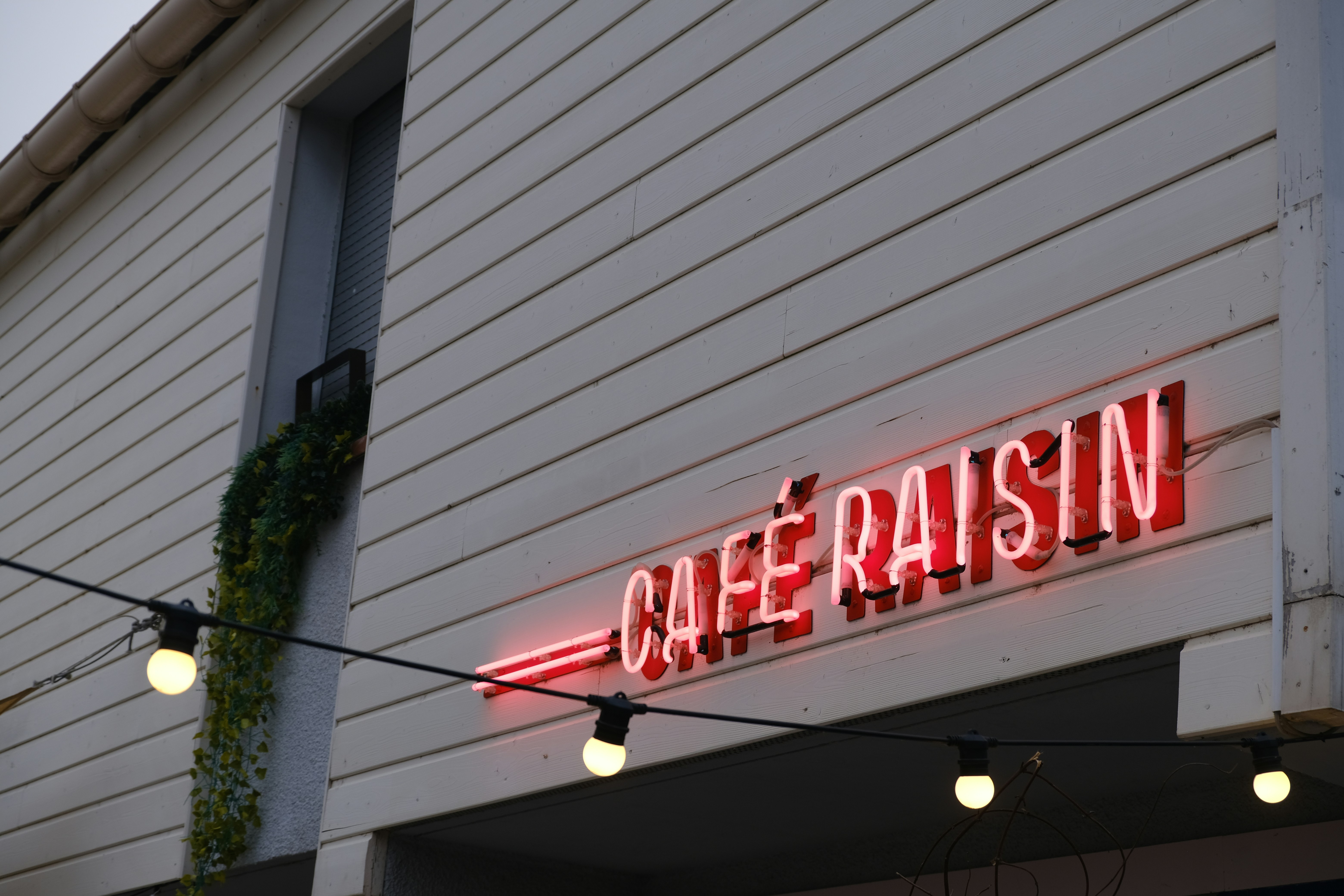Neon Café Sign, Warm Glow Across Weathered Siding