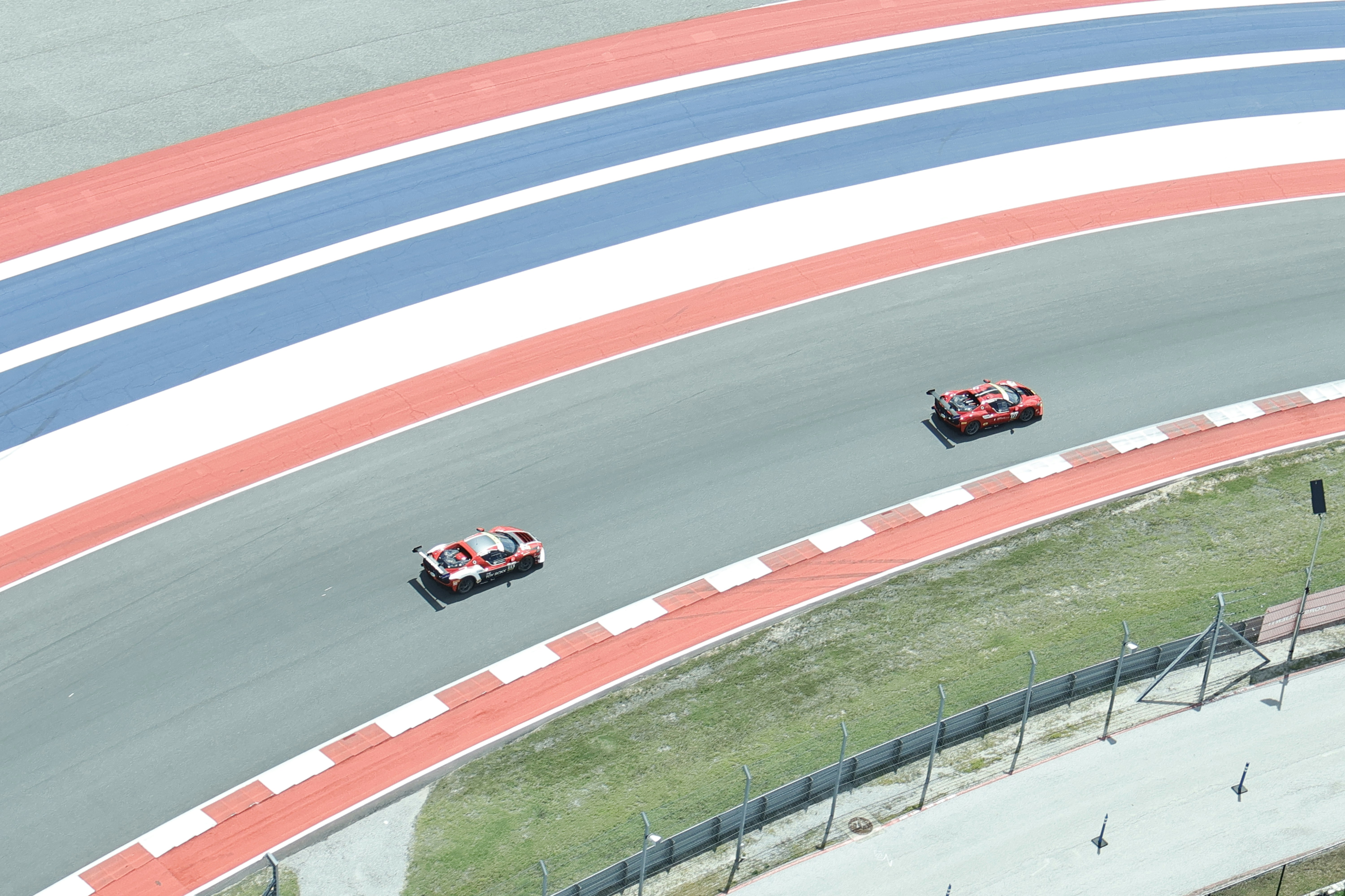 Aerial Sprint: Two Race Cars Climb the Red-White Striped Curve