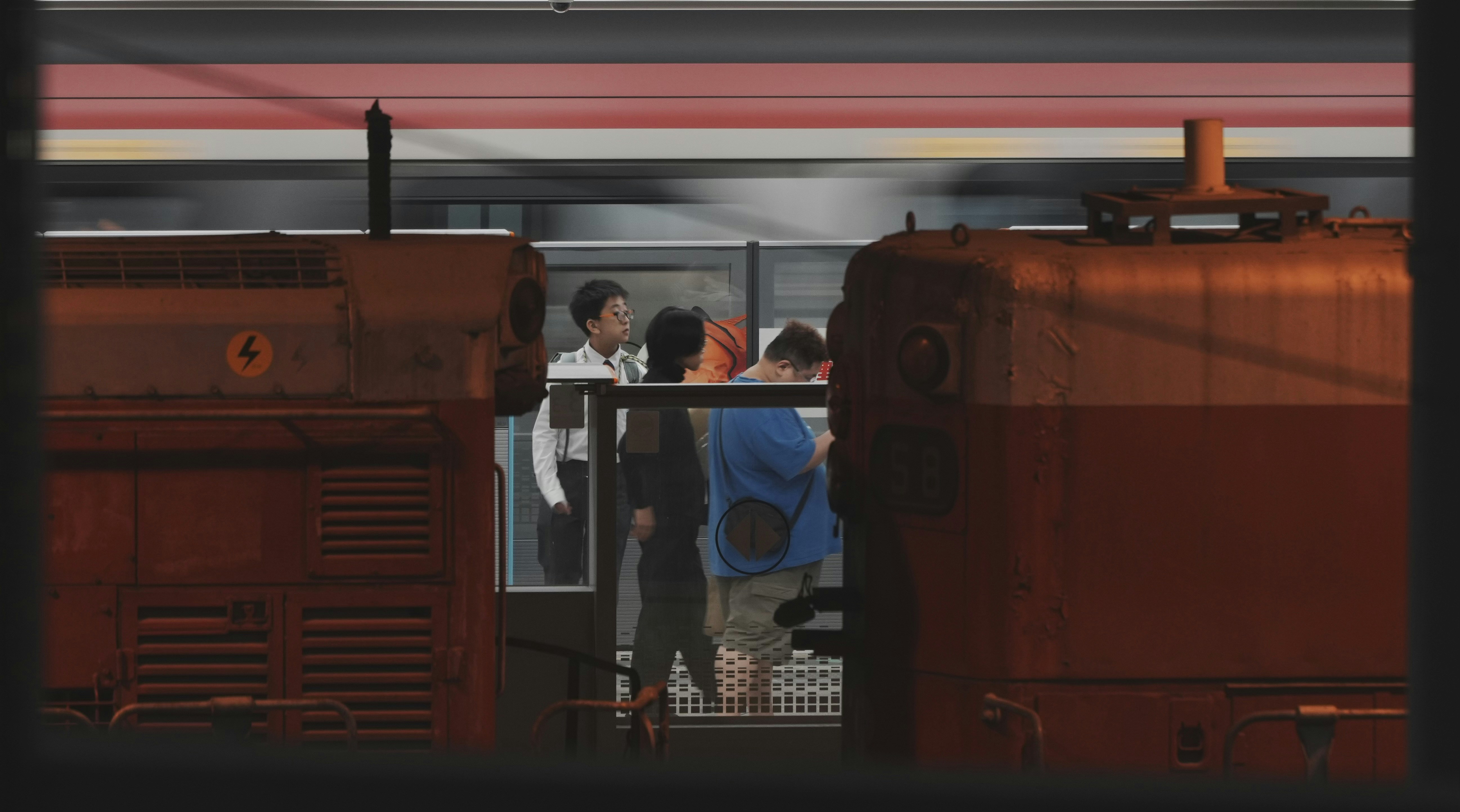Passengers framed between industrial reds in motion