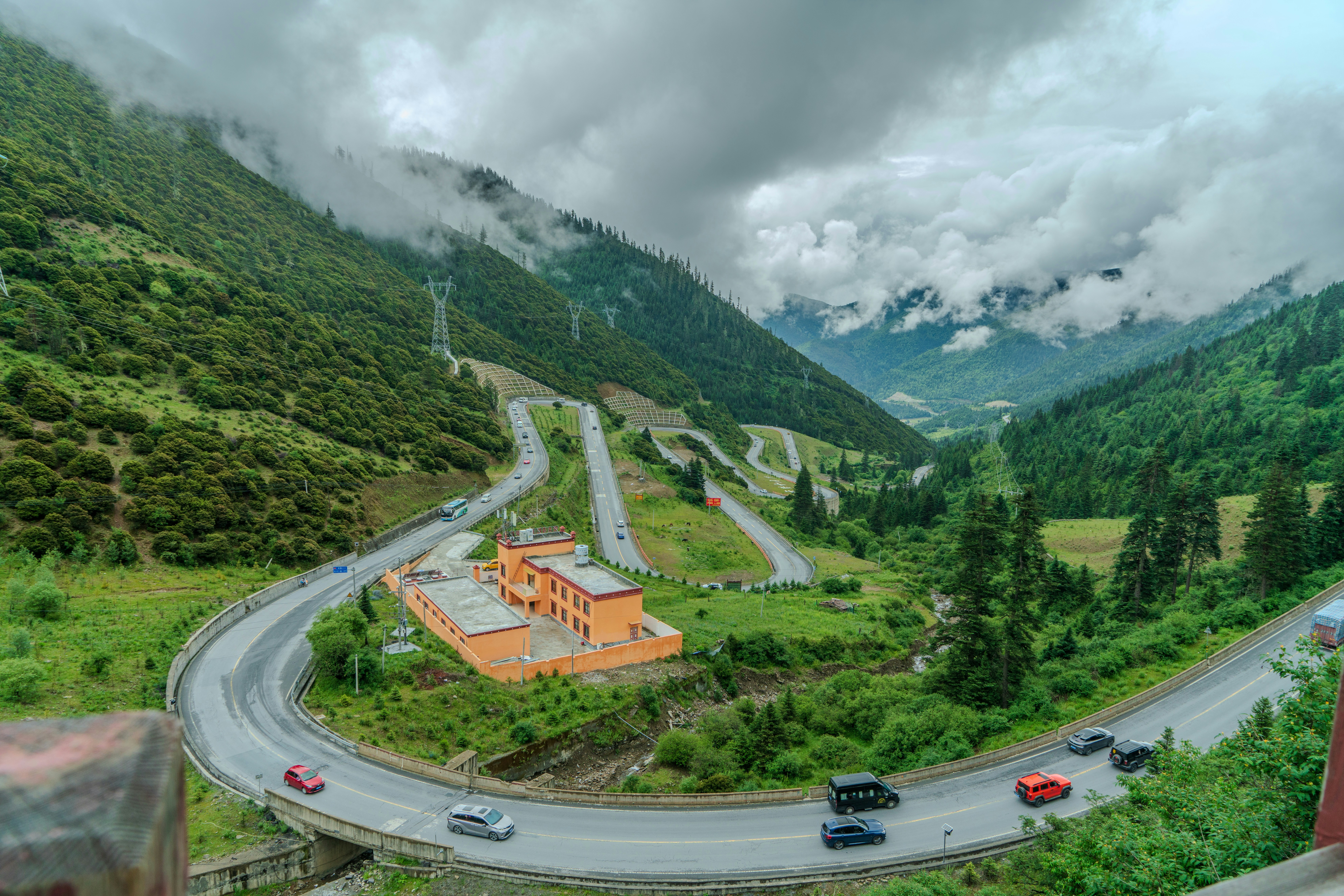 Coiled Alpine Boulevard: A Winding Road Through Misty Green Valleys