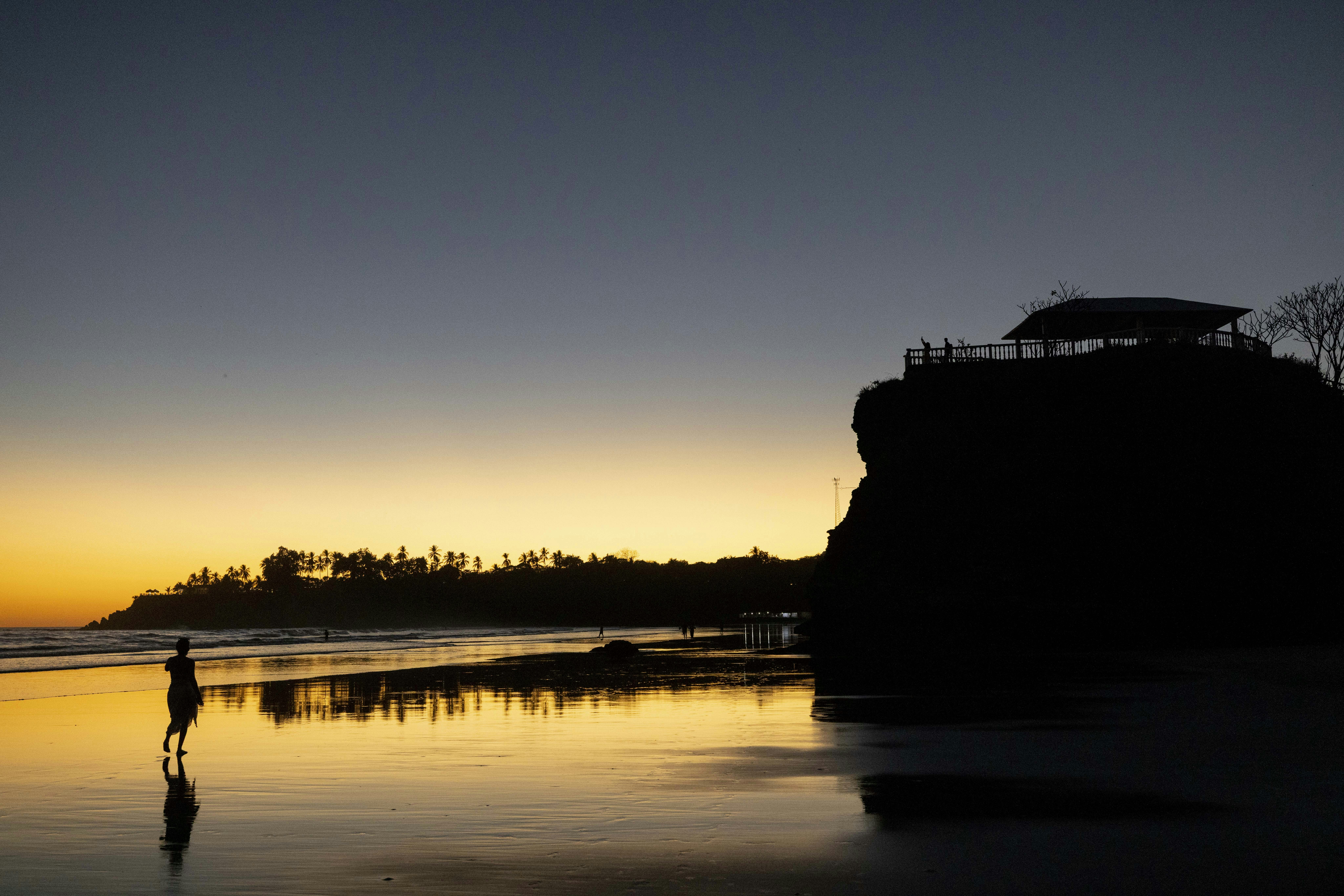 Silhouette by the Shore: A Lone Fisherman at Dusk