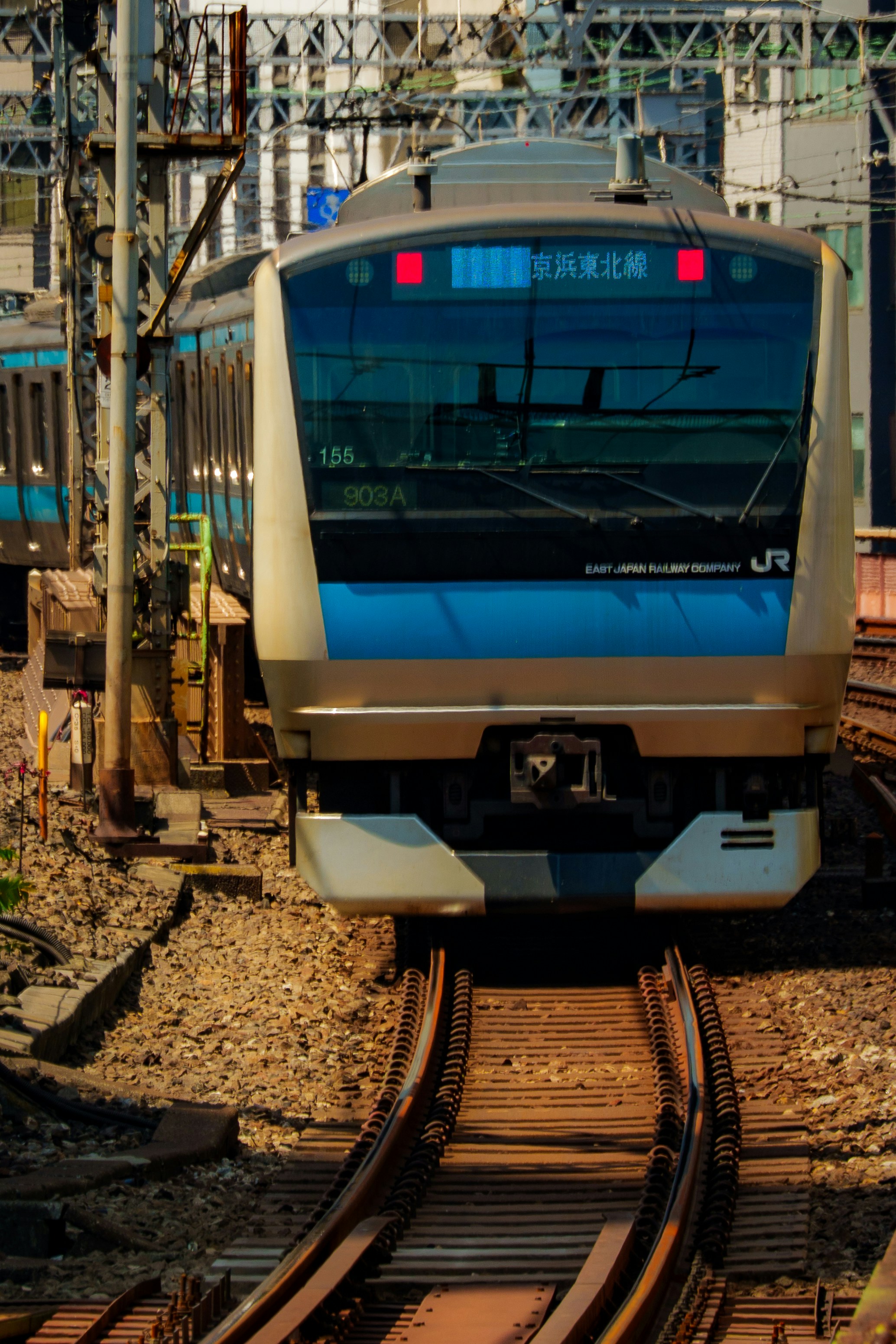 Front view of a commuter train nearing the camera on a sunlit track