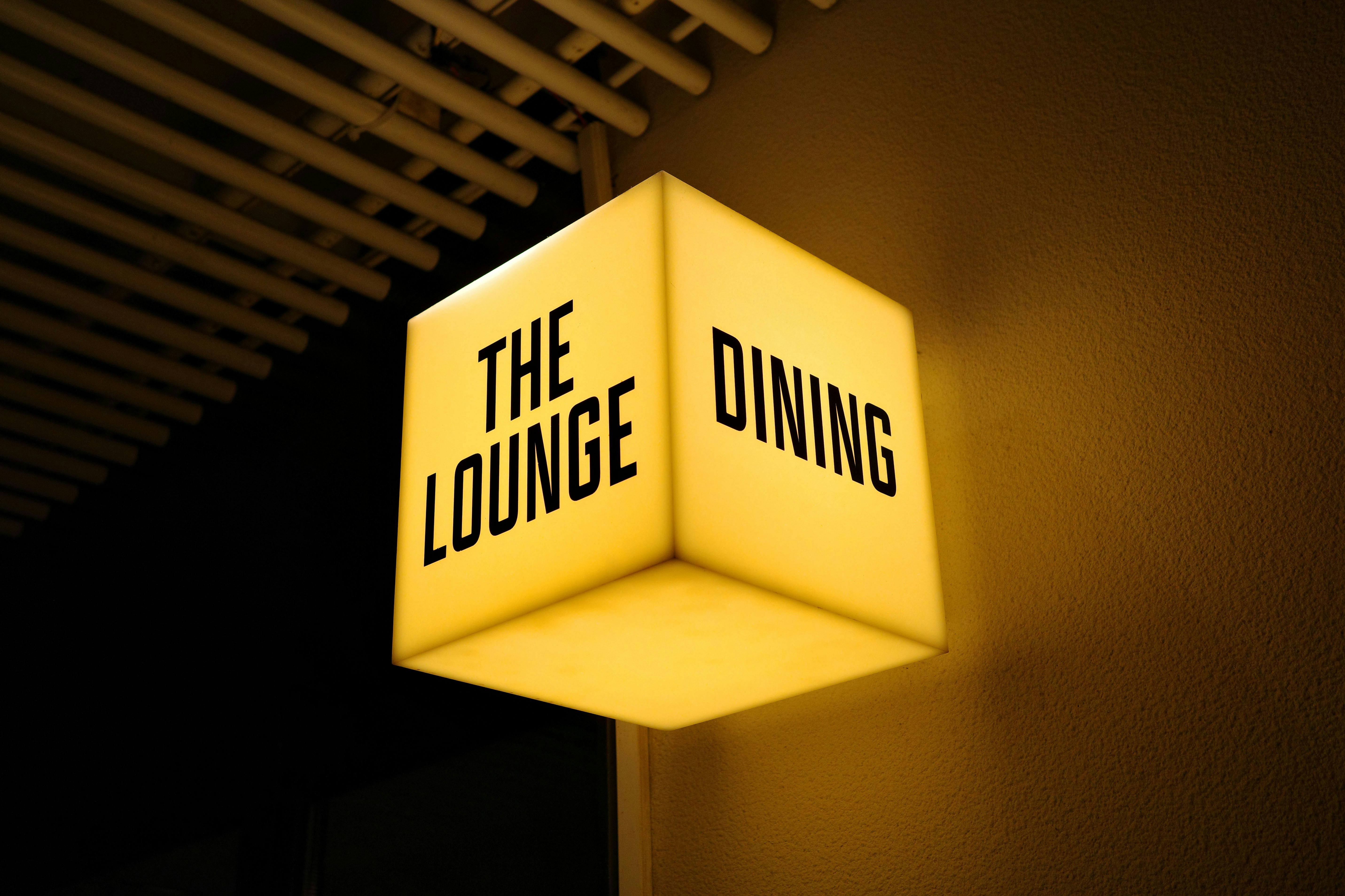 Lit Signpost: The Lounge Dining Emblem in Soft Night Glow