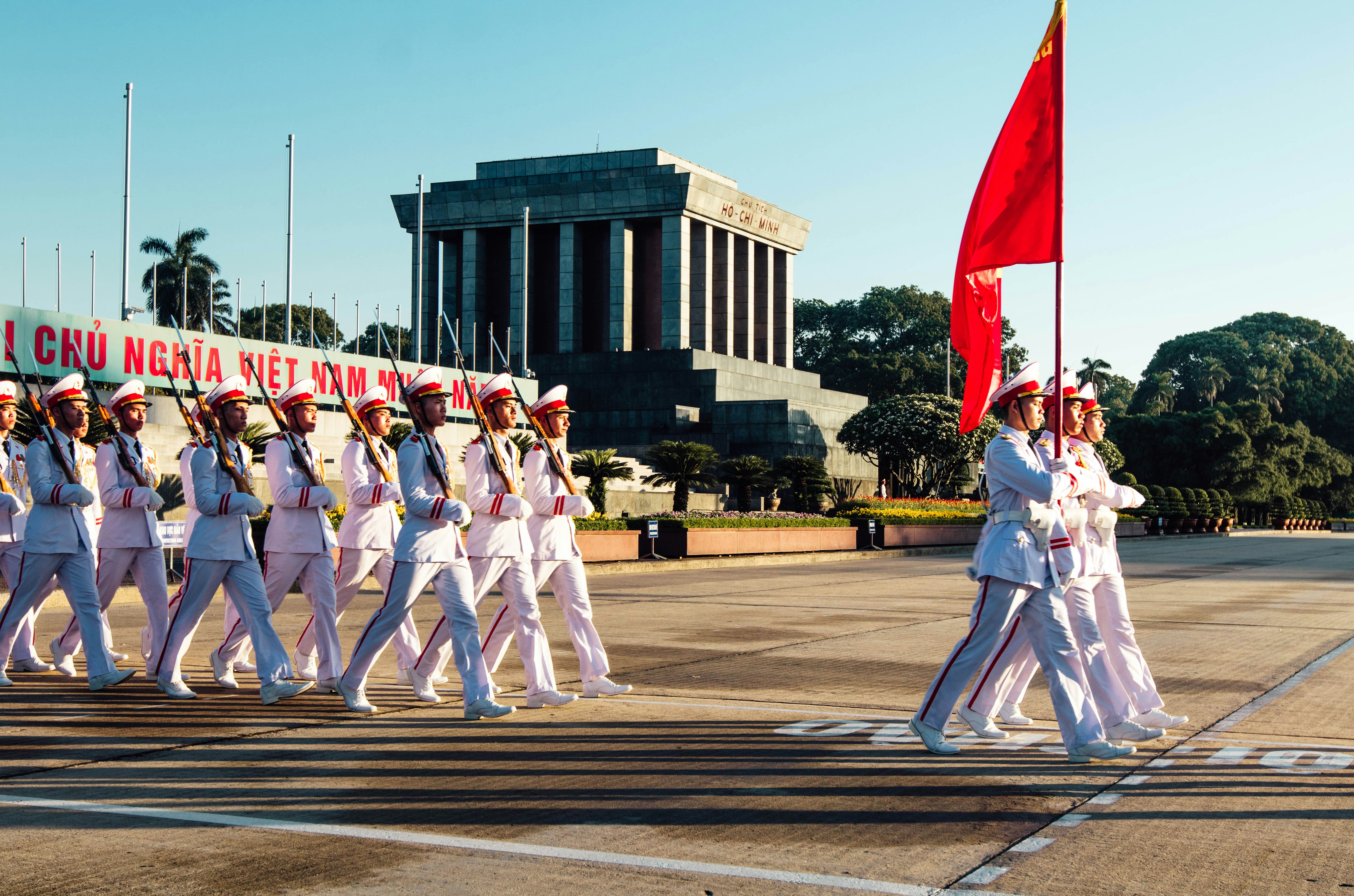 Military Parade: White uniforms march past a monumental memorial under a bright Vietnamese sky