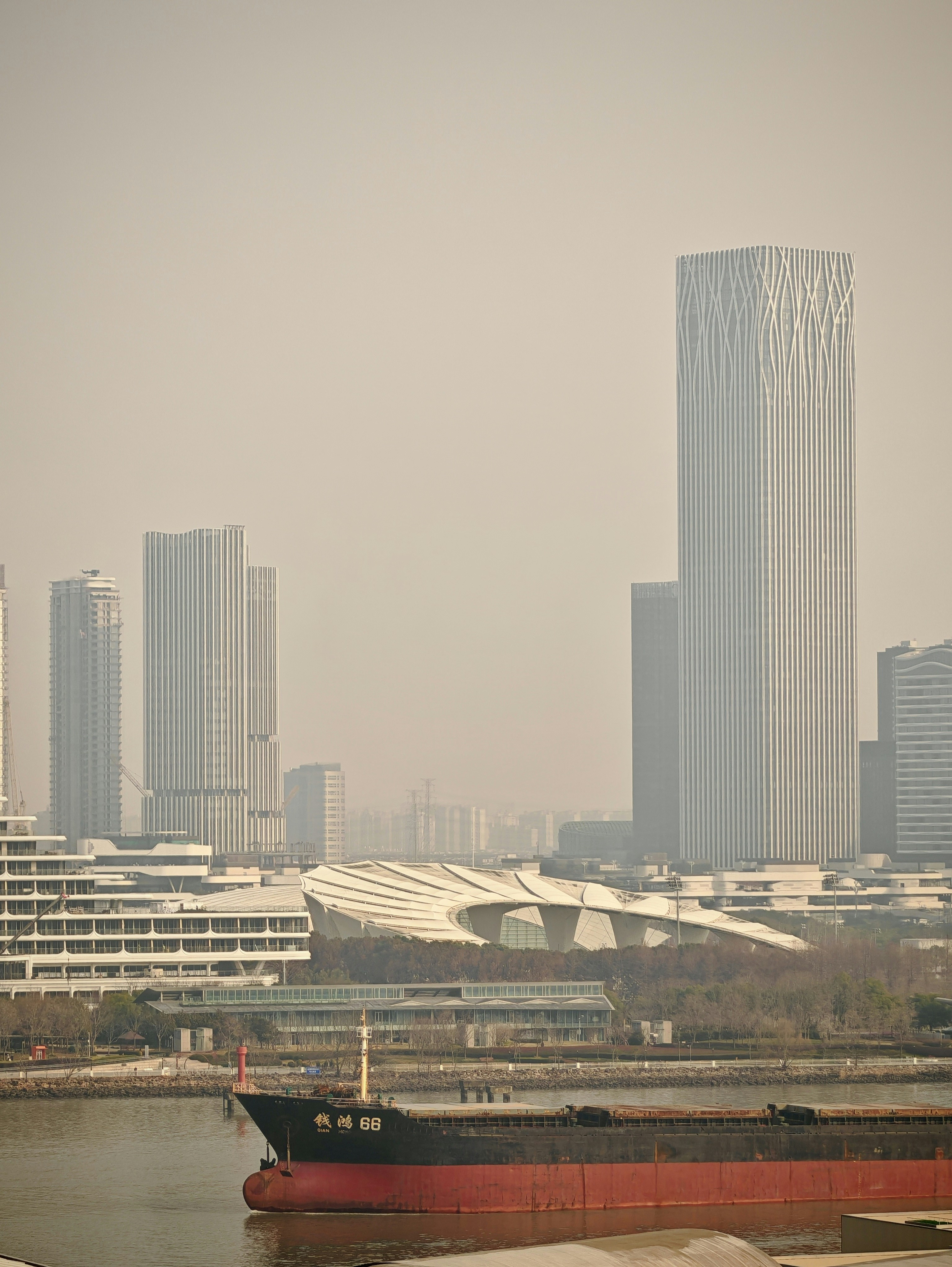 Riverfront Skyline with Tall Geometric Tower Under a Misty Dawn