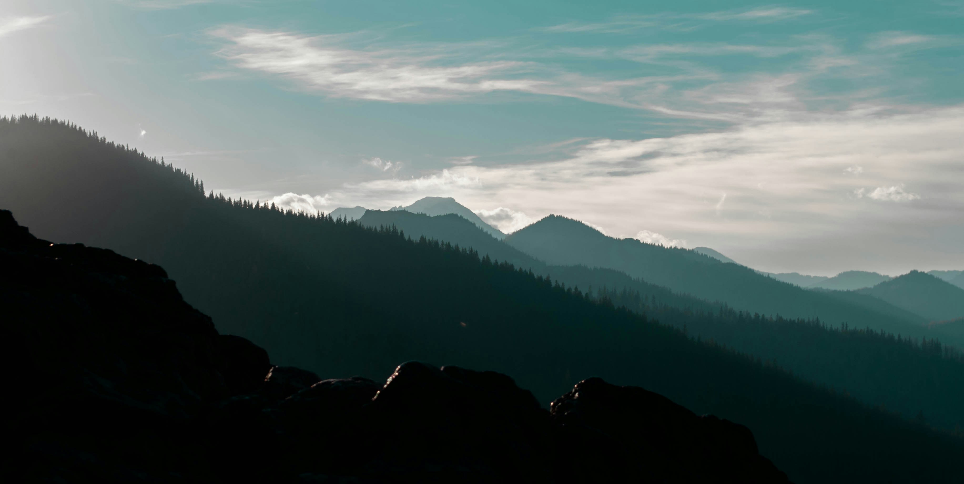 Silhouette of mountain ridges under a pale blue sky