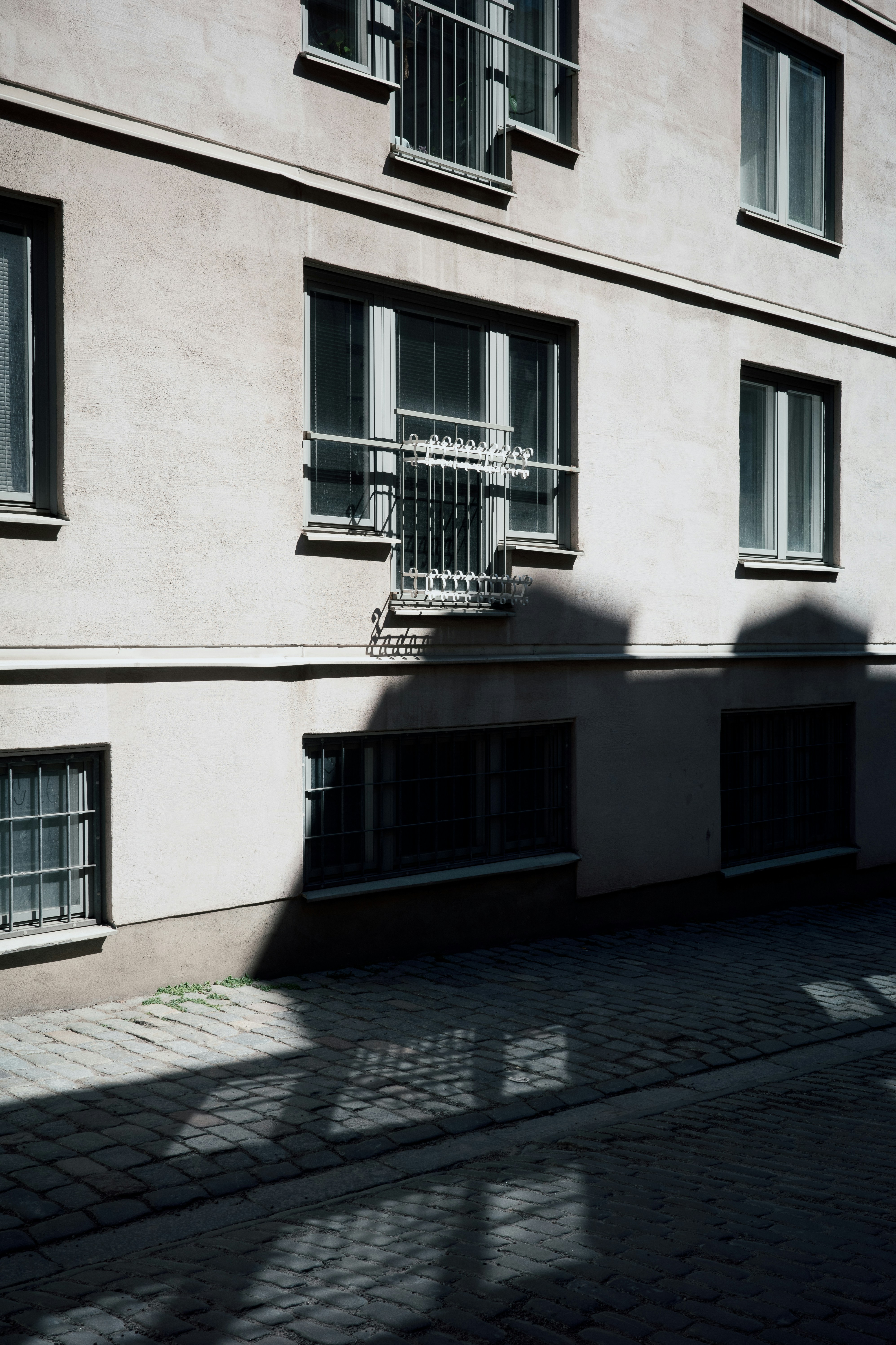 Shadowed Balcony over a Pebbled Street