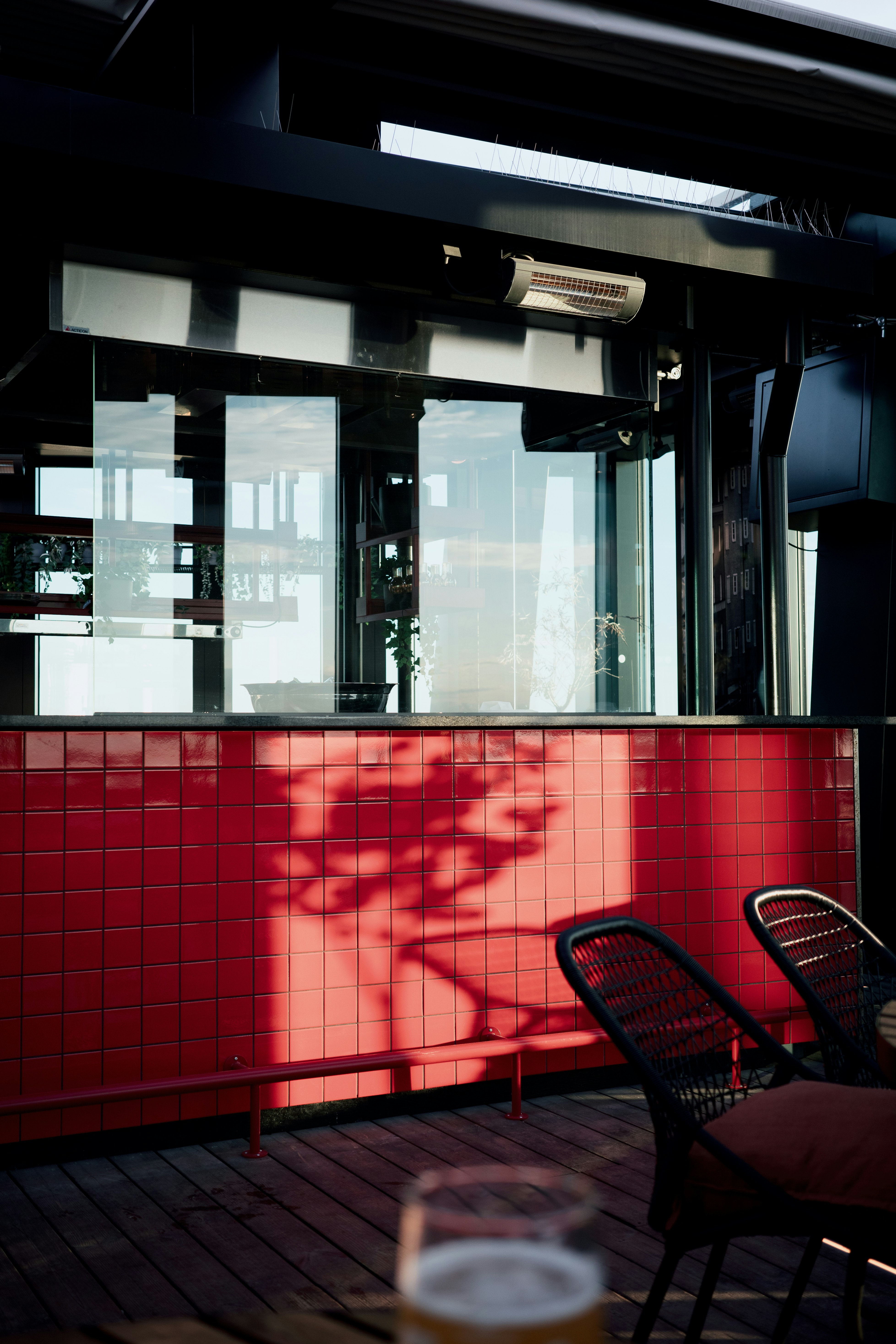Red tiled wall and geometric windows framing a sunlit courtyard scene