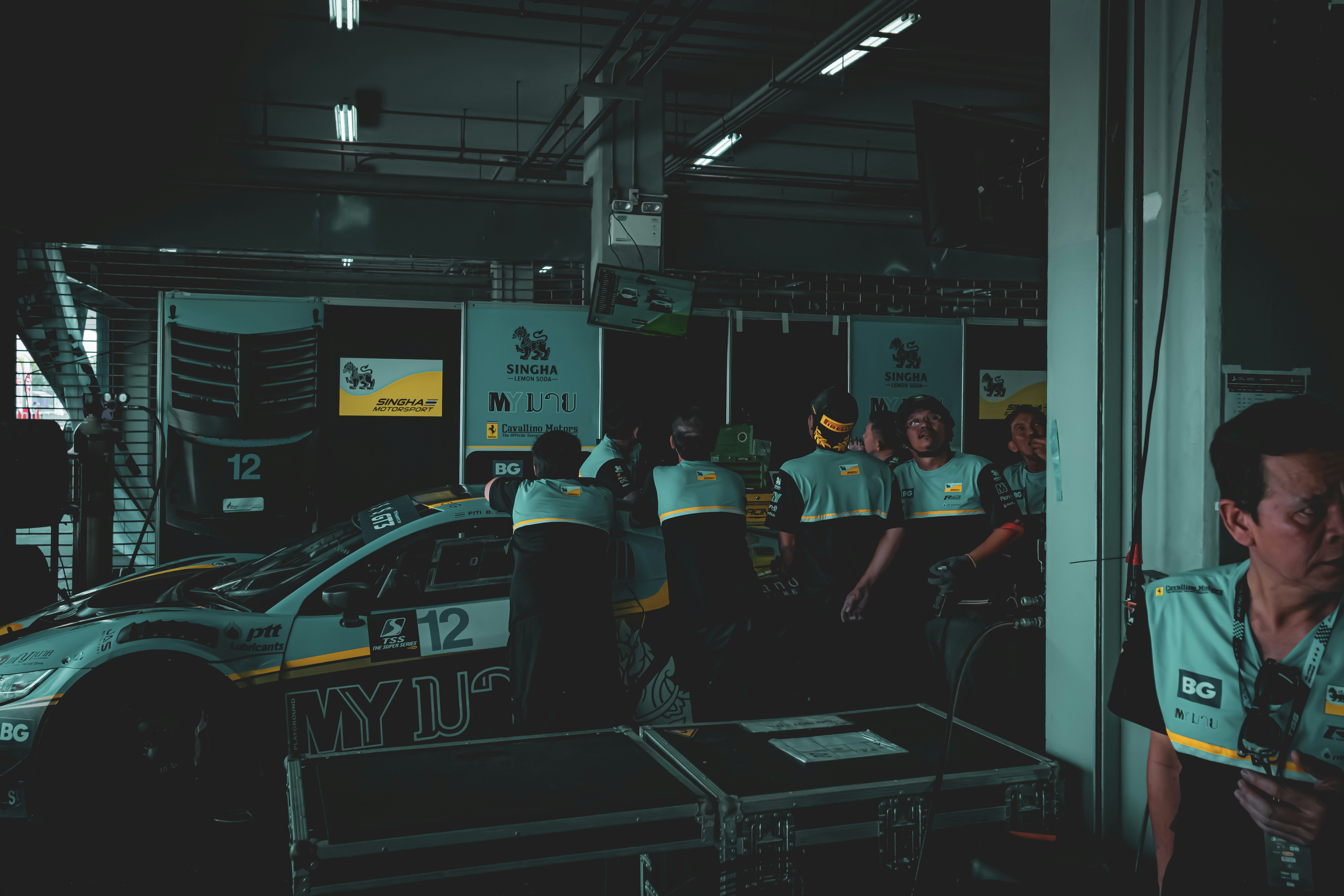 Pit Crew in the Shadowed Pit Lane
