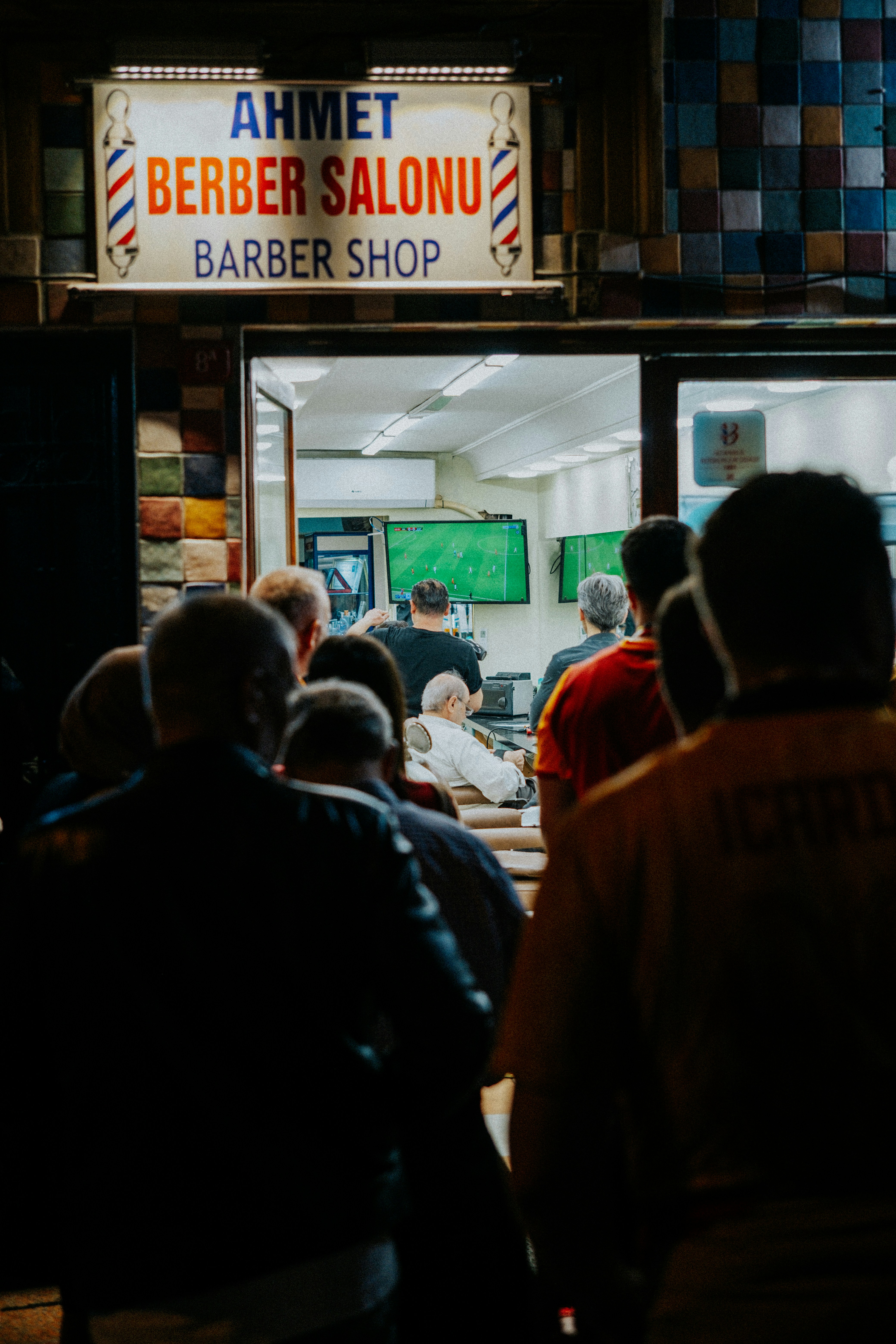 A line of people waiting outside a barber shop