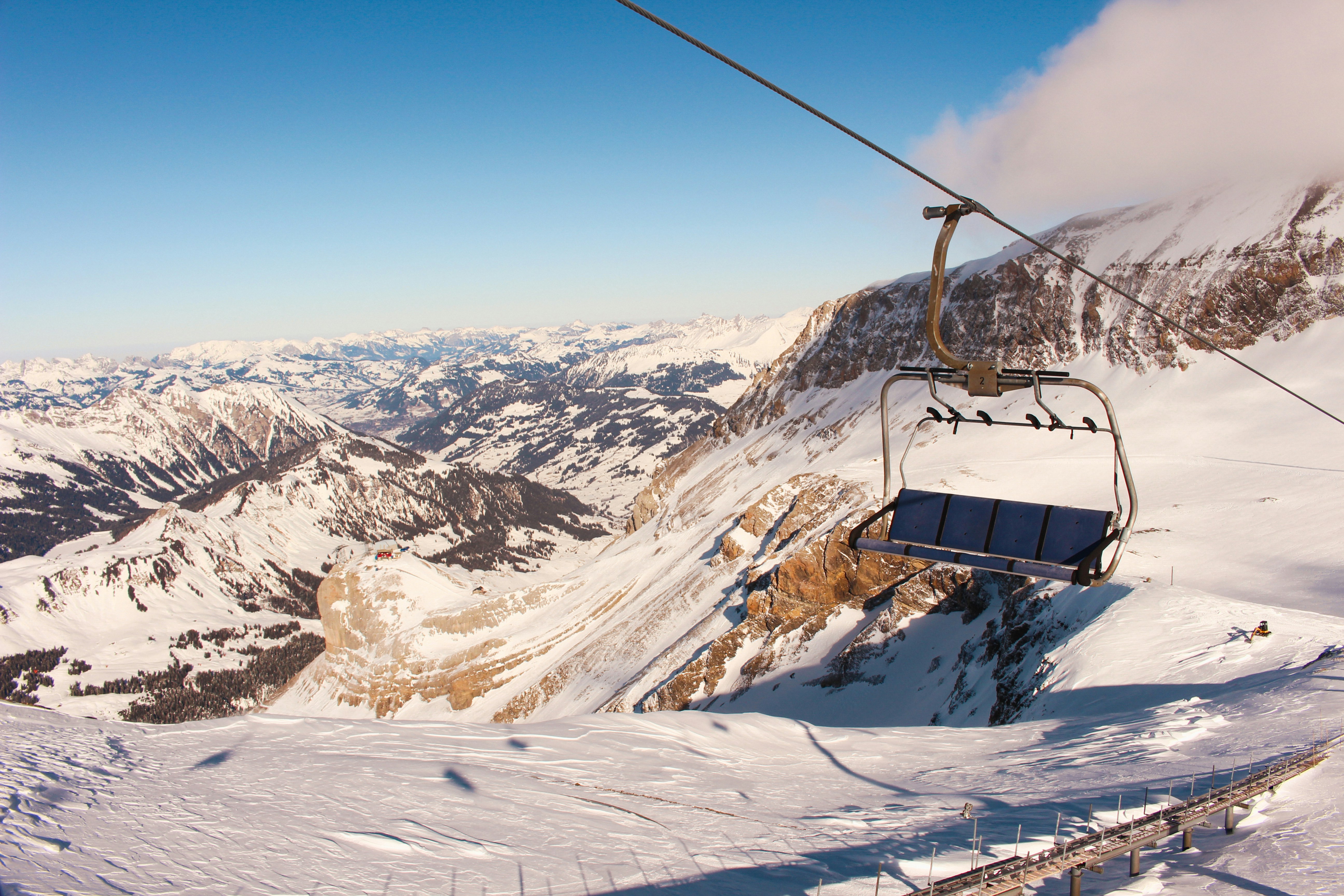 Empty ski lift chair over snowy mountains and valleys.