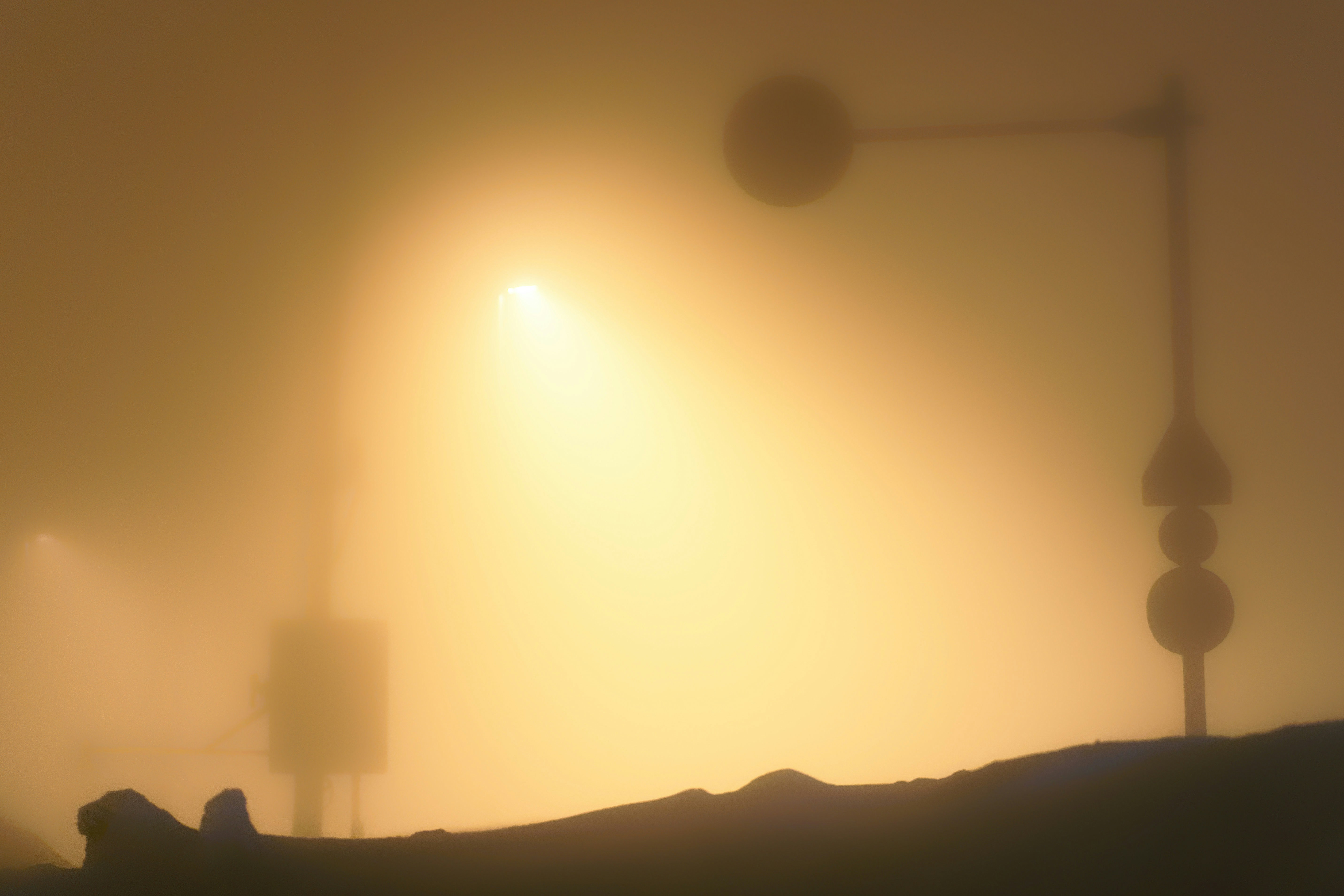 Fog-lit railyard at dawn with distant signaling silhouette