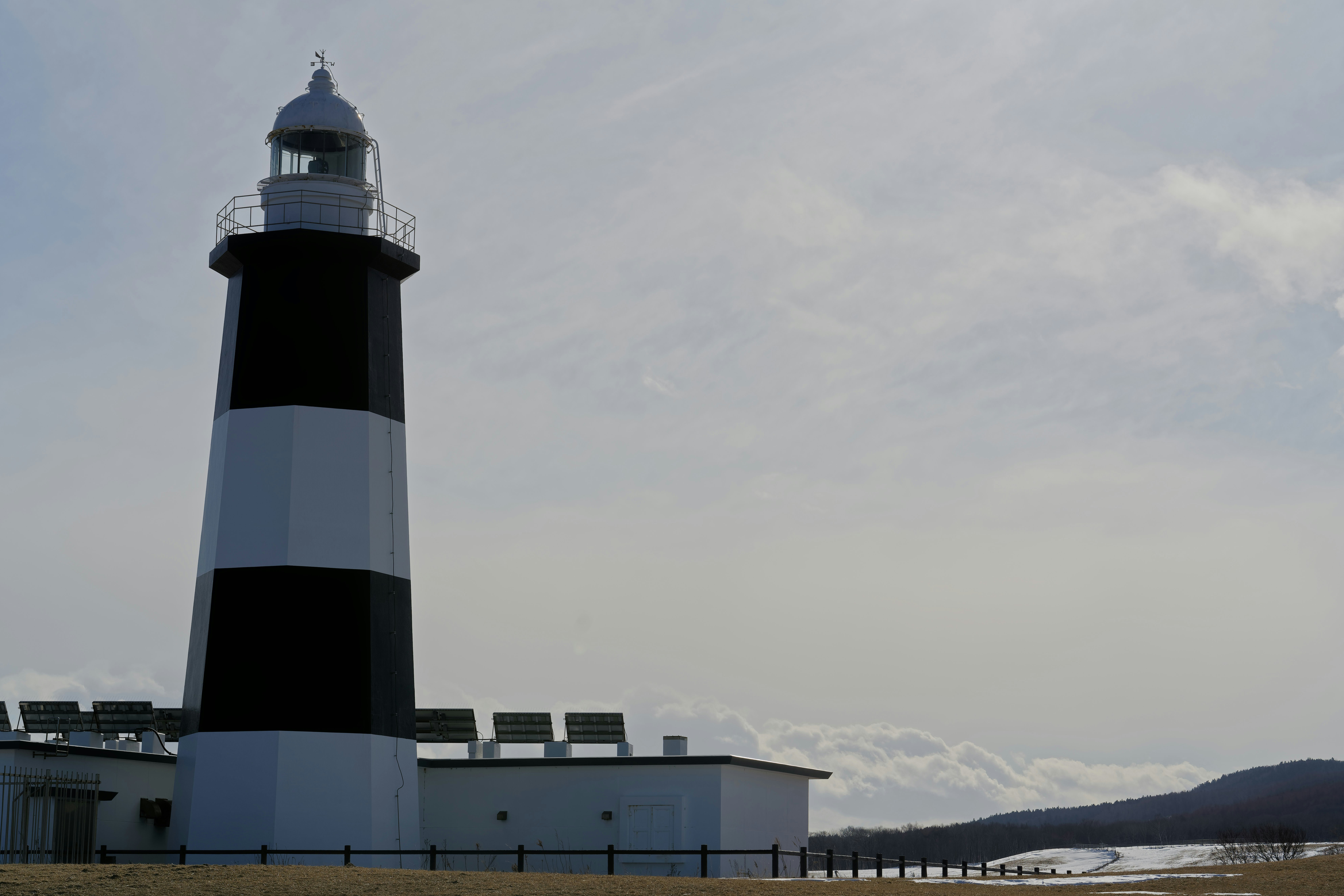 Coastal Beacon: A Striped Lighthouse Standing Against an Open Sky