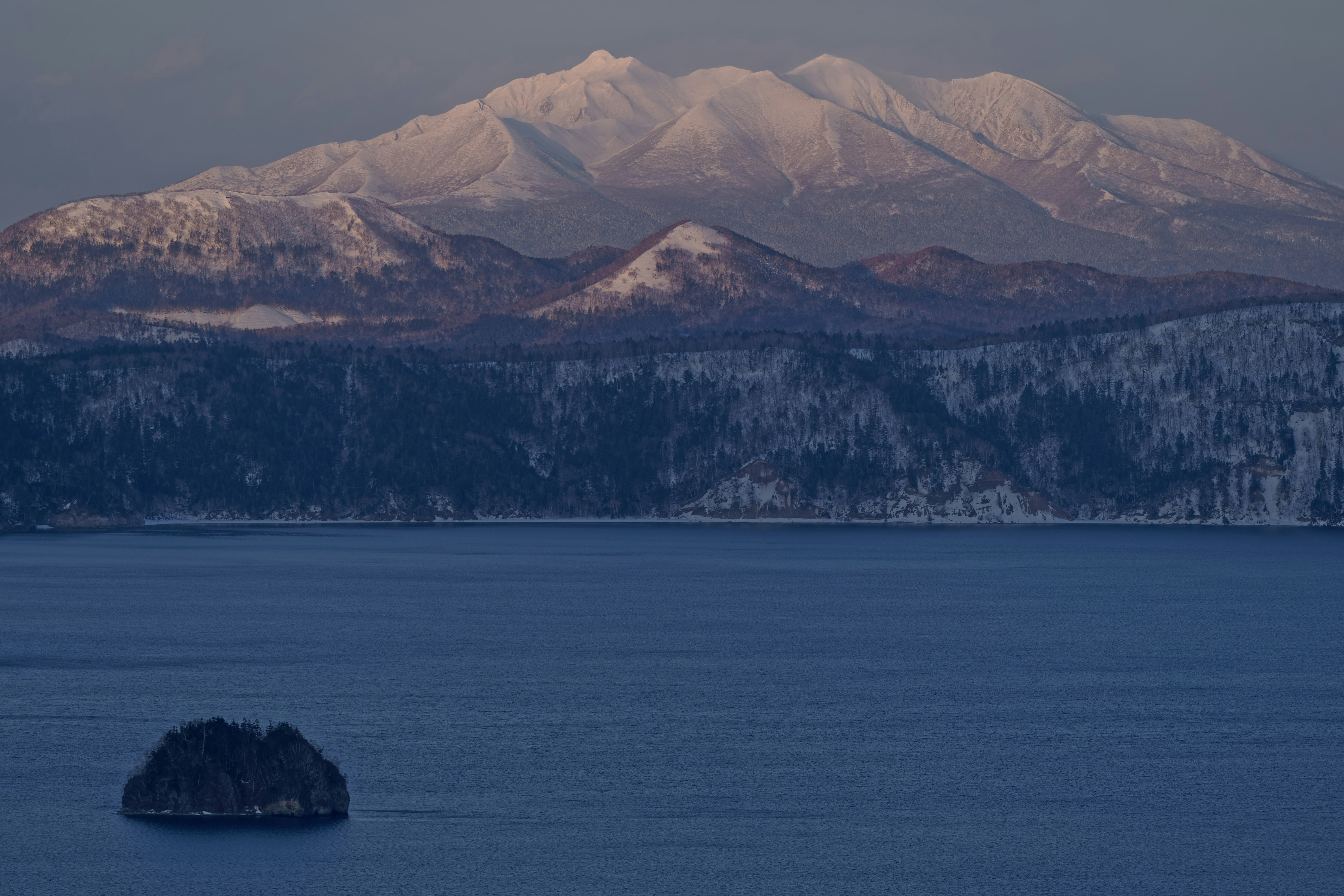 Snow-kissed peak horizon over midnight blue lake