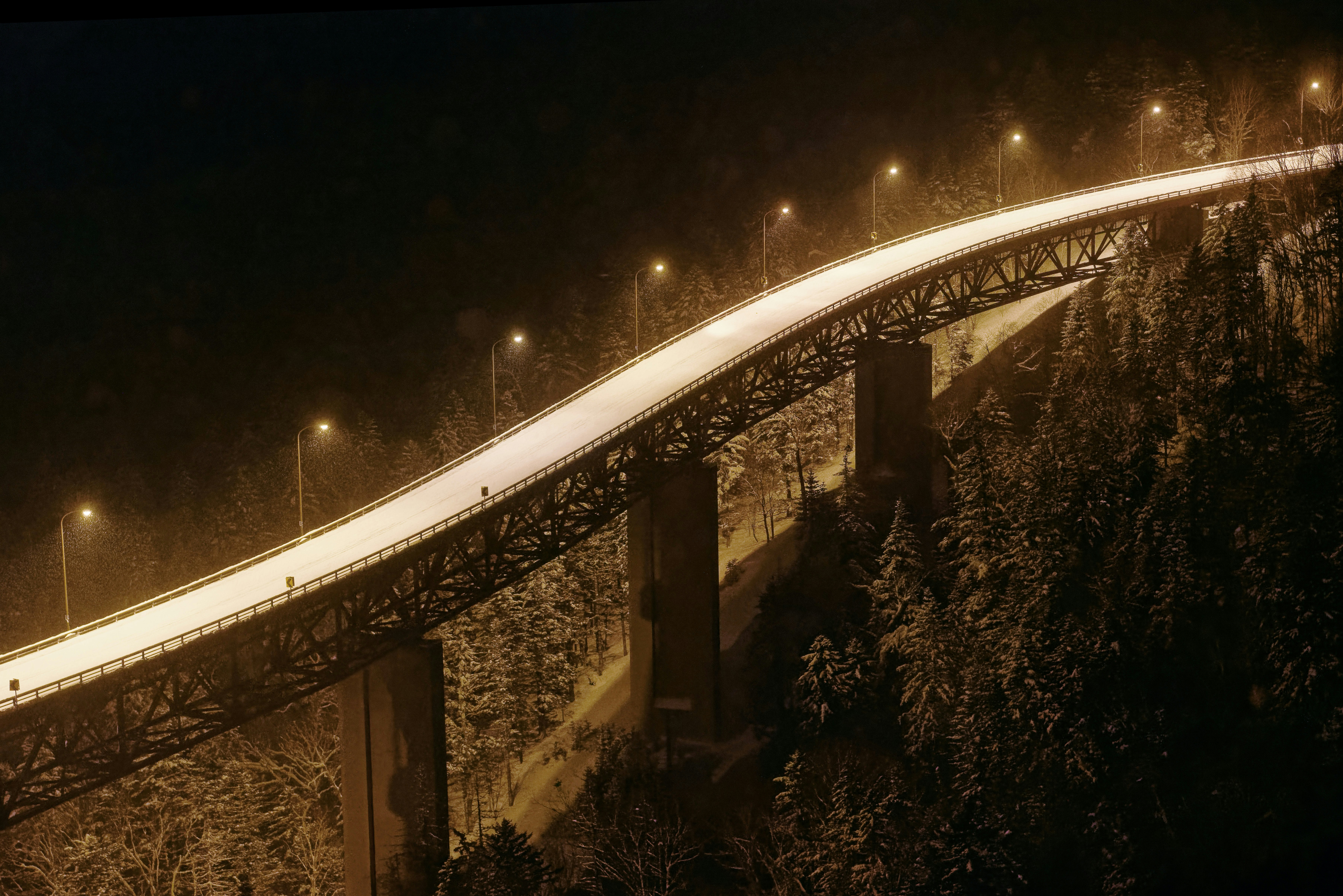 Night Arc: The Glowing Bridge Curling Over a Snowy Ravine