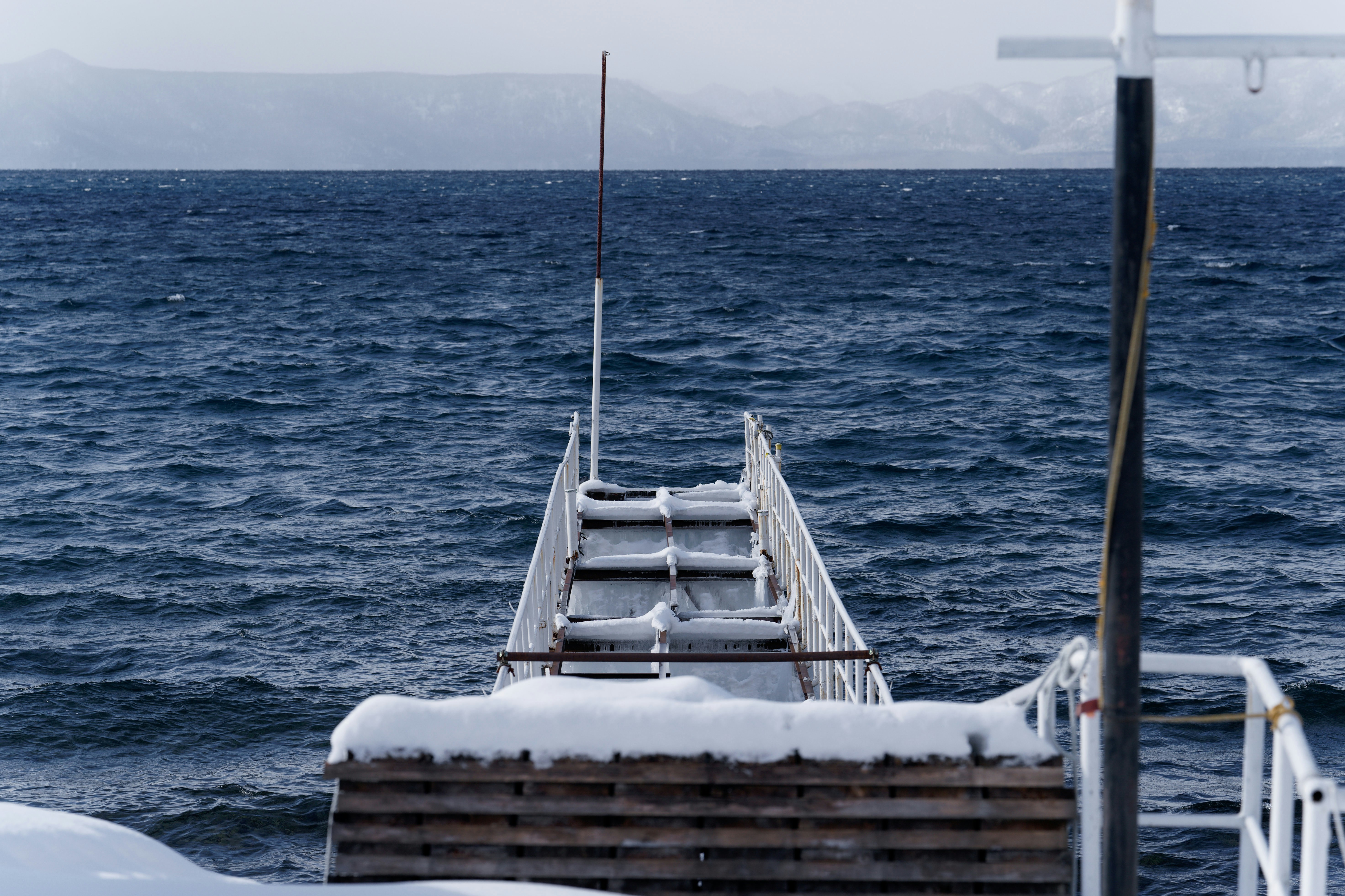 Snow-Capped Pier Reaching Toward a Distant Sea