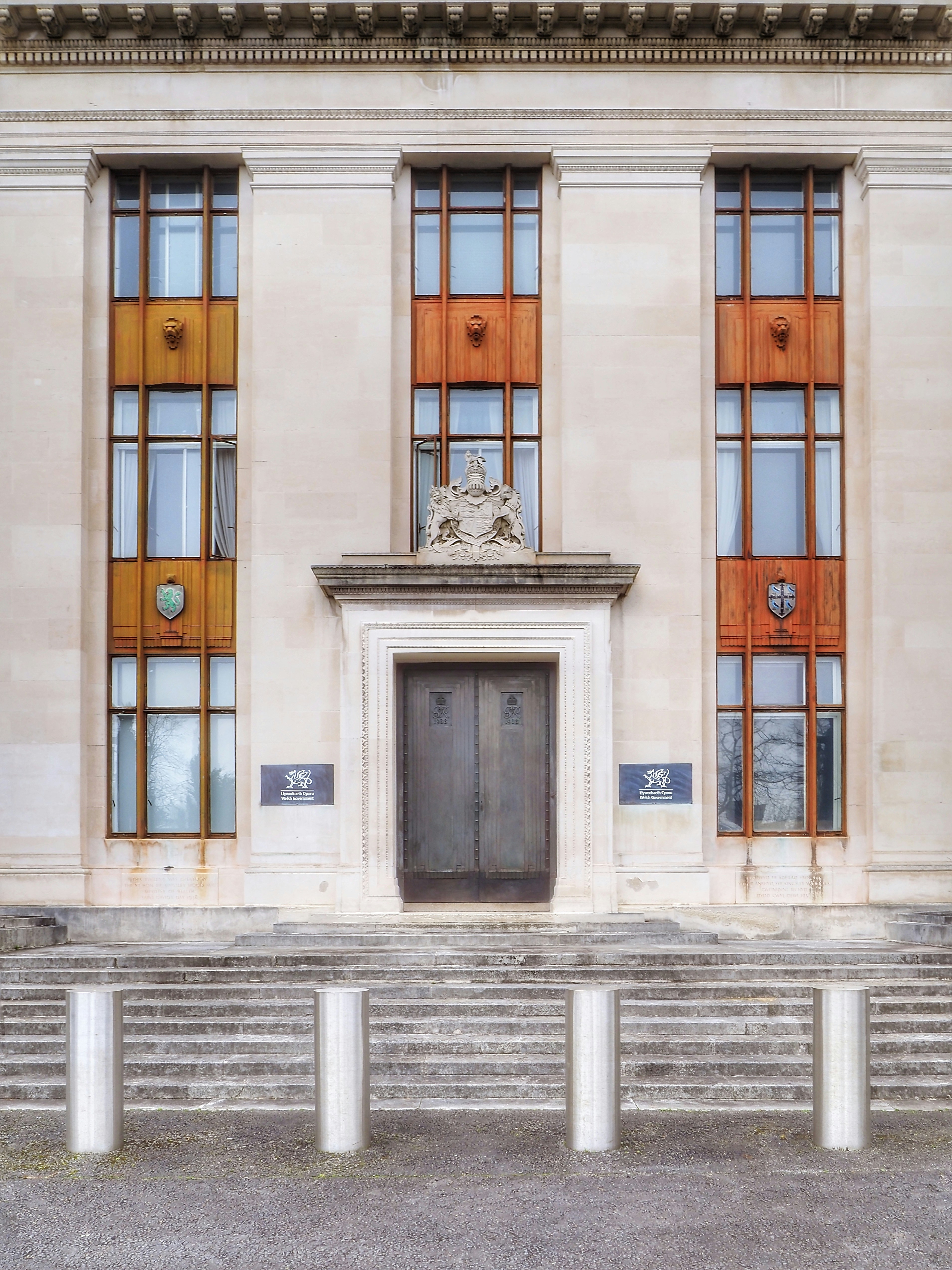 Entrance of a neoclassical facade framed by tall wooden windows and stone steps