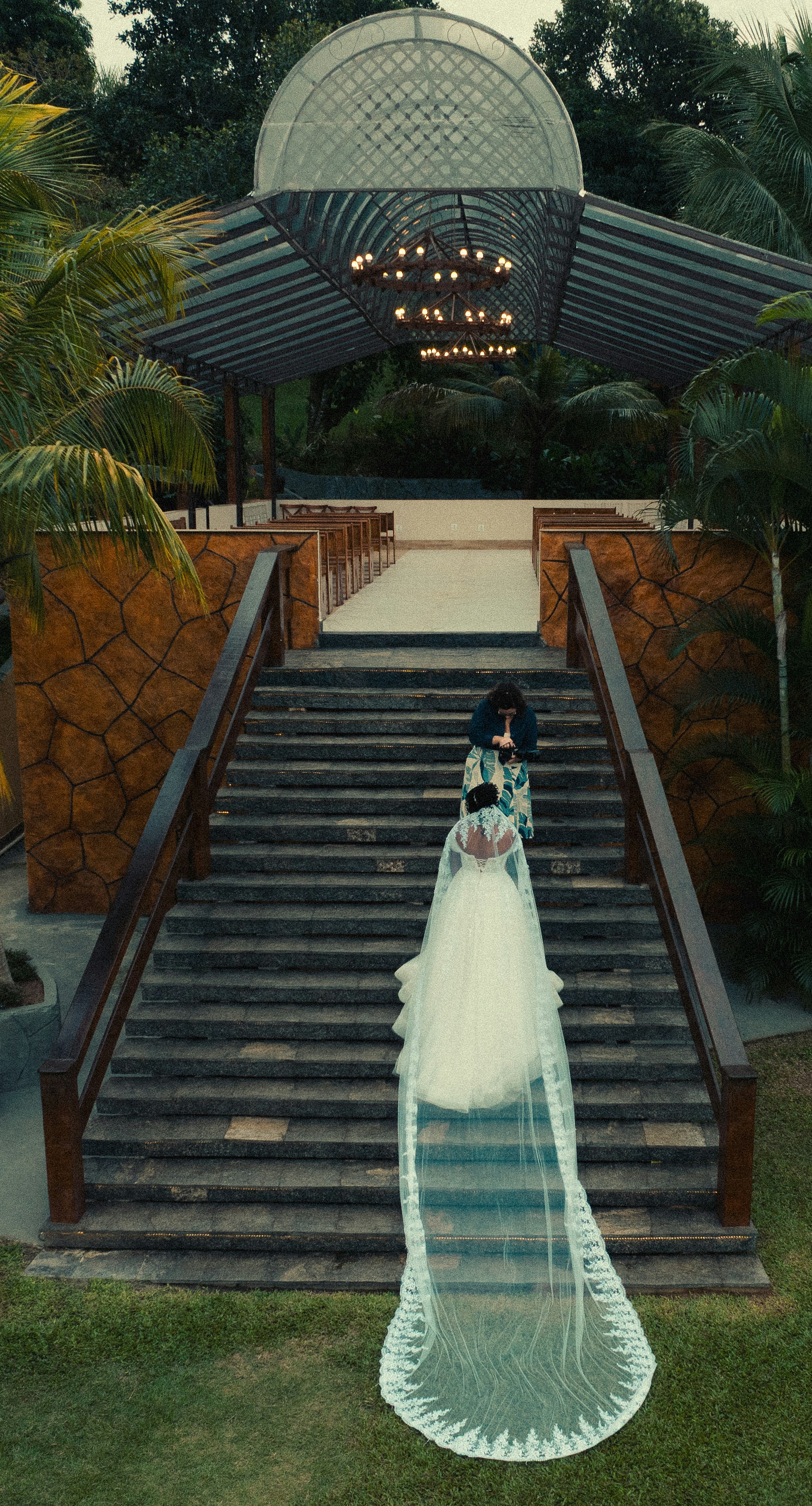 Elegant bride walking up stairs with a flowing veil.