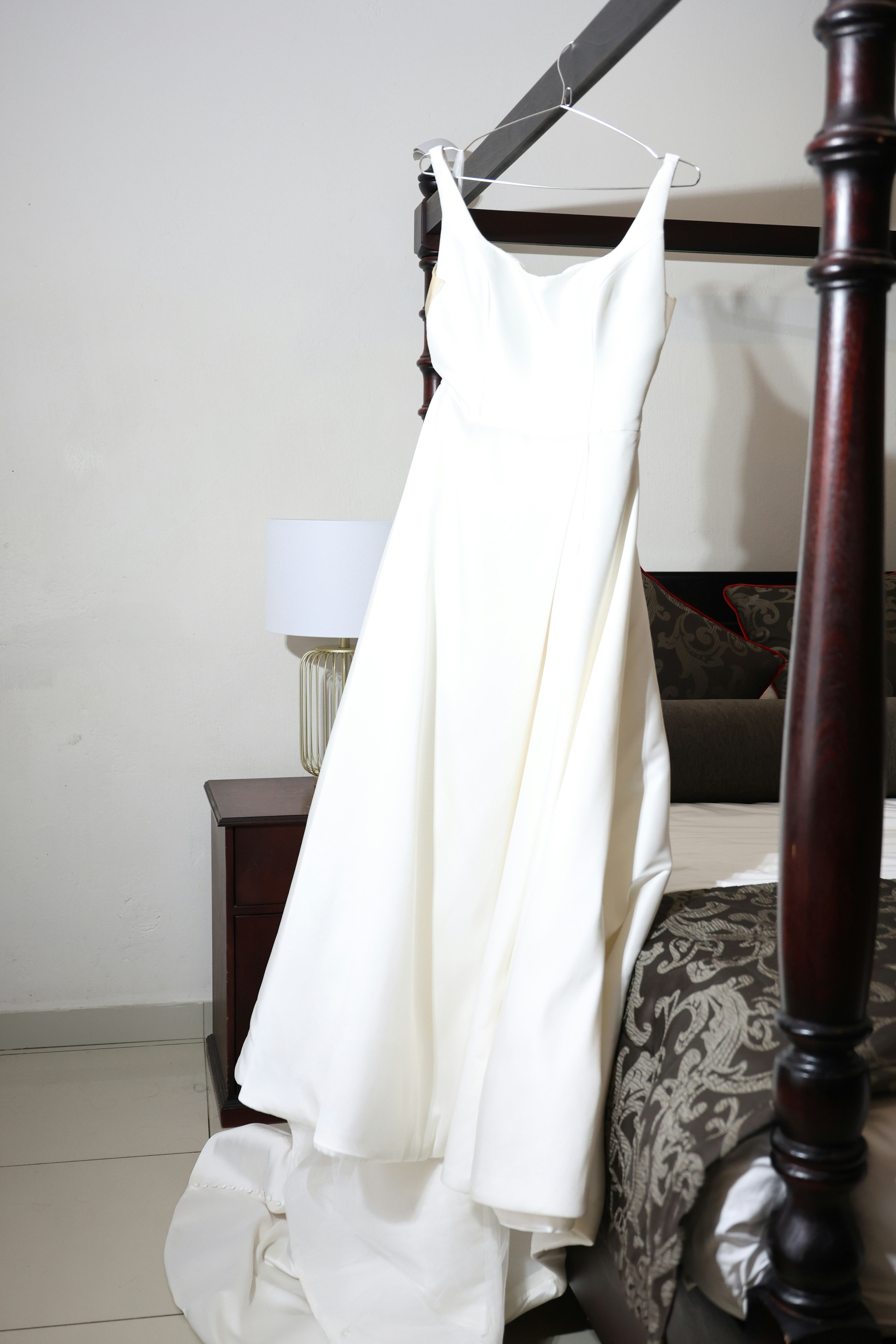 White wedding gown on a rustic four-poster frame in a softly lit bedroom