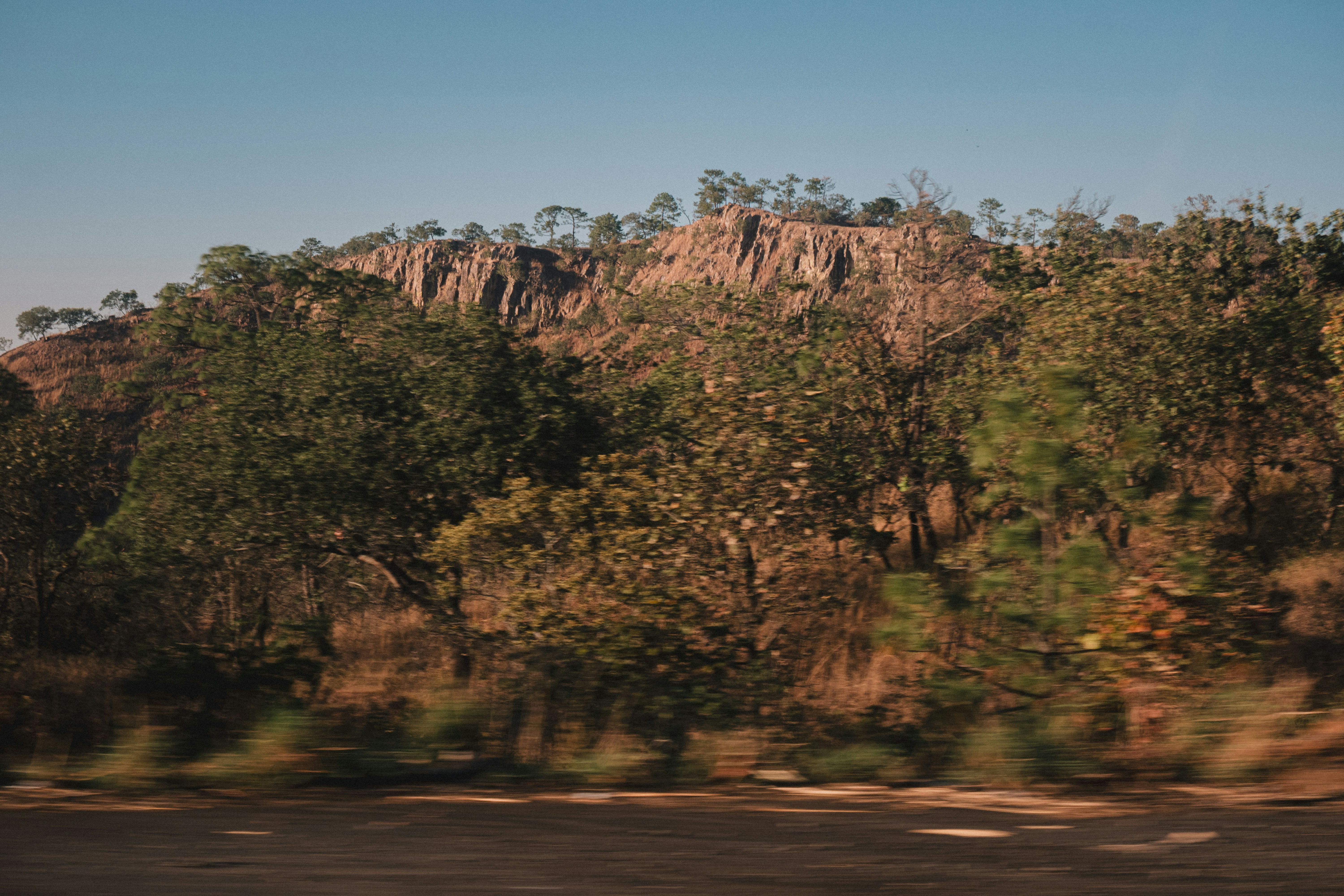 Ridgeline Quiet: A Sunlit Cliff Above a Blurred Desert Road