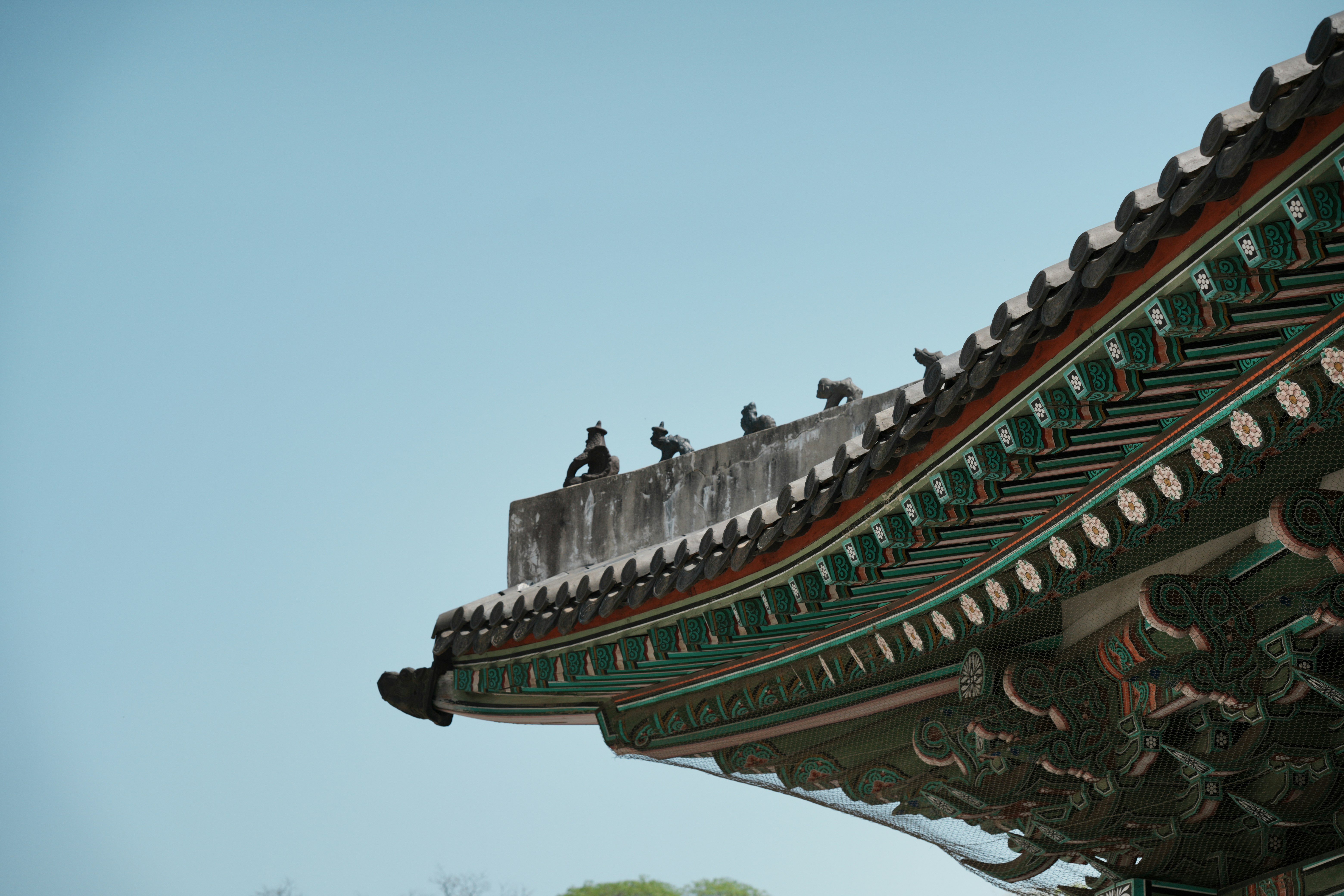 Ornate traditional korean temple roof against a clear blue sky.