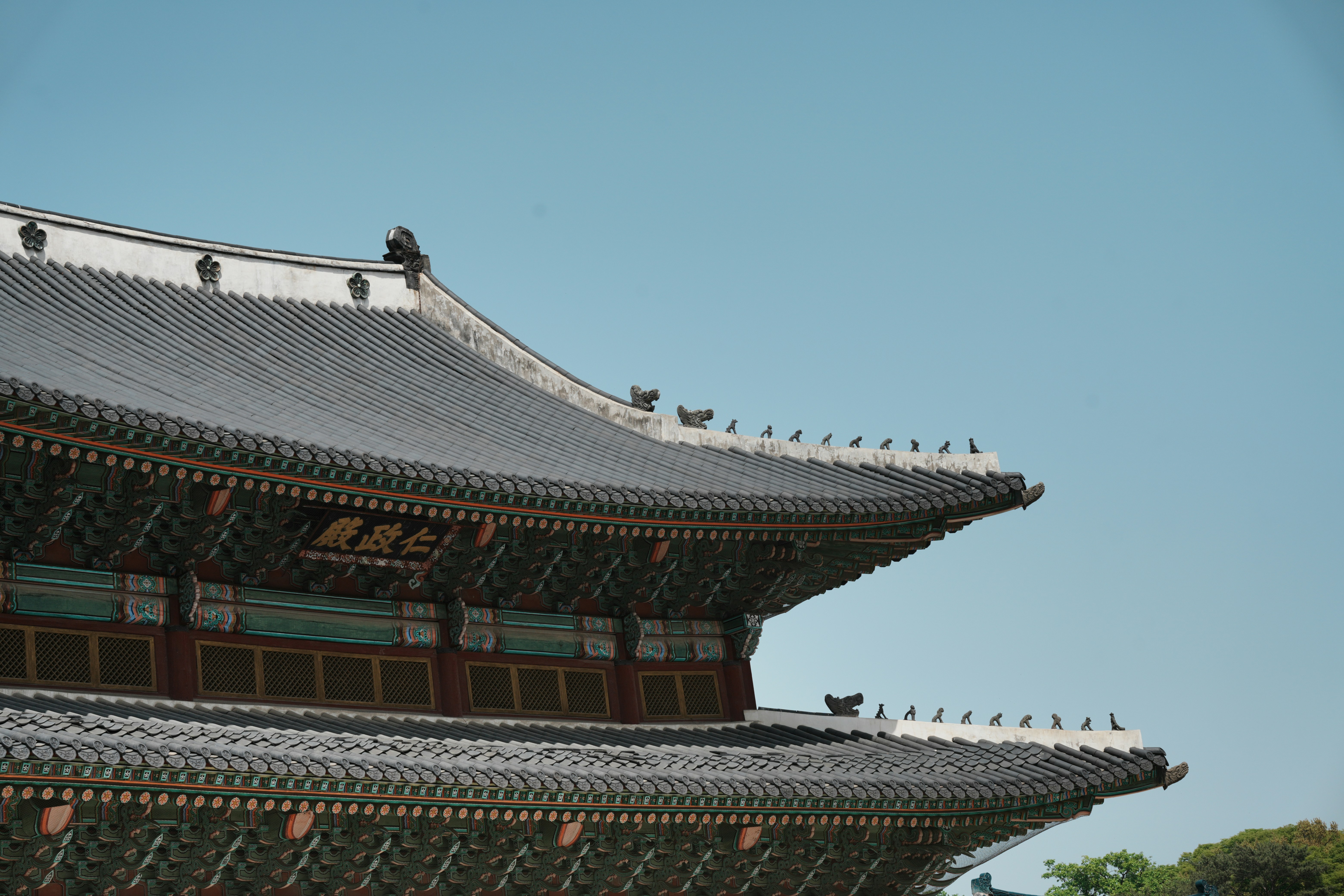 Traditional korean palace roof against a clear blue sky.
