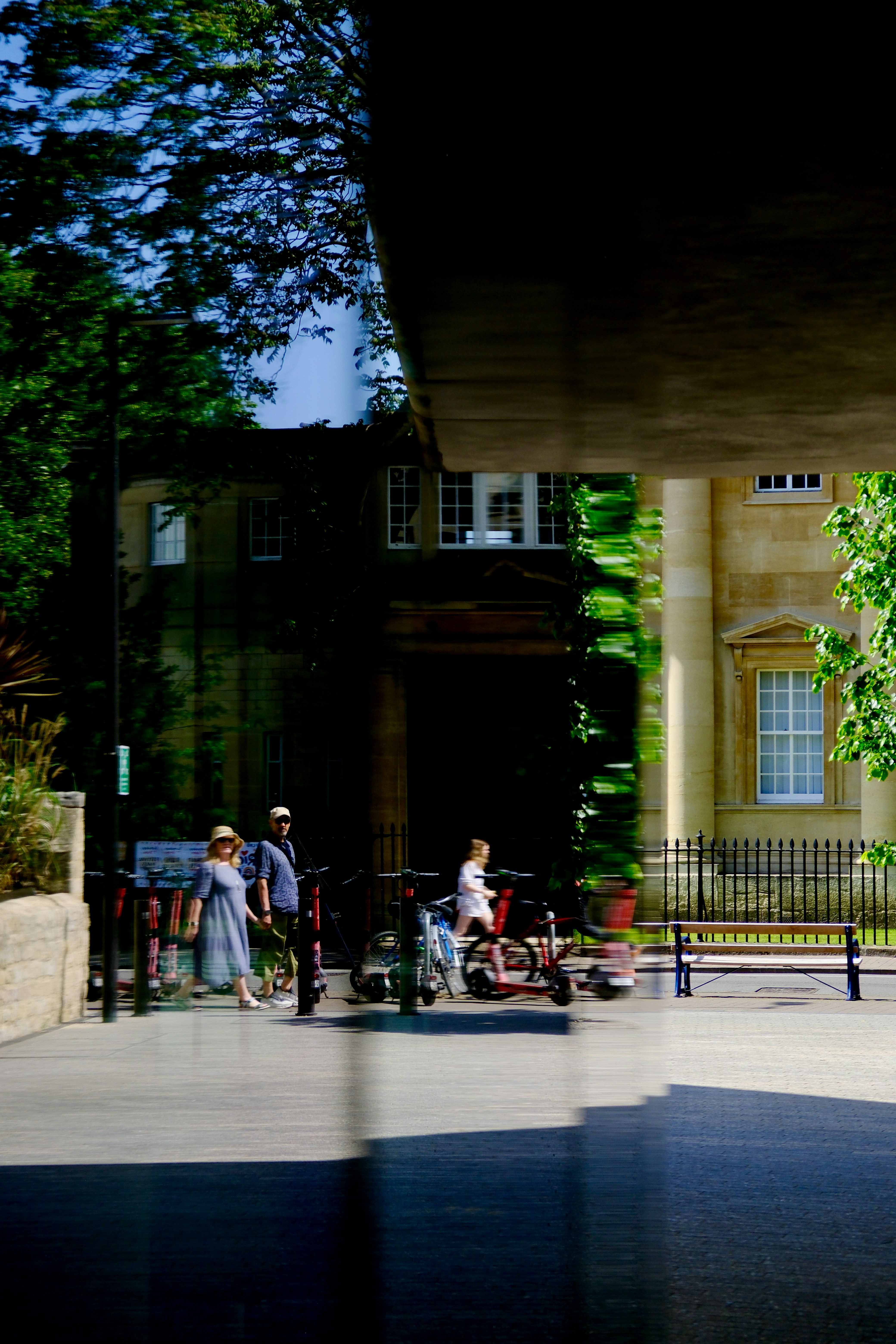 Shadows Over the Courtyard: People and Bicycles in Dappled Light